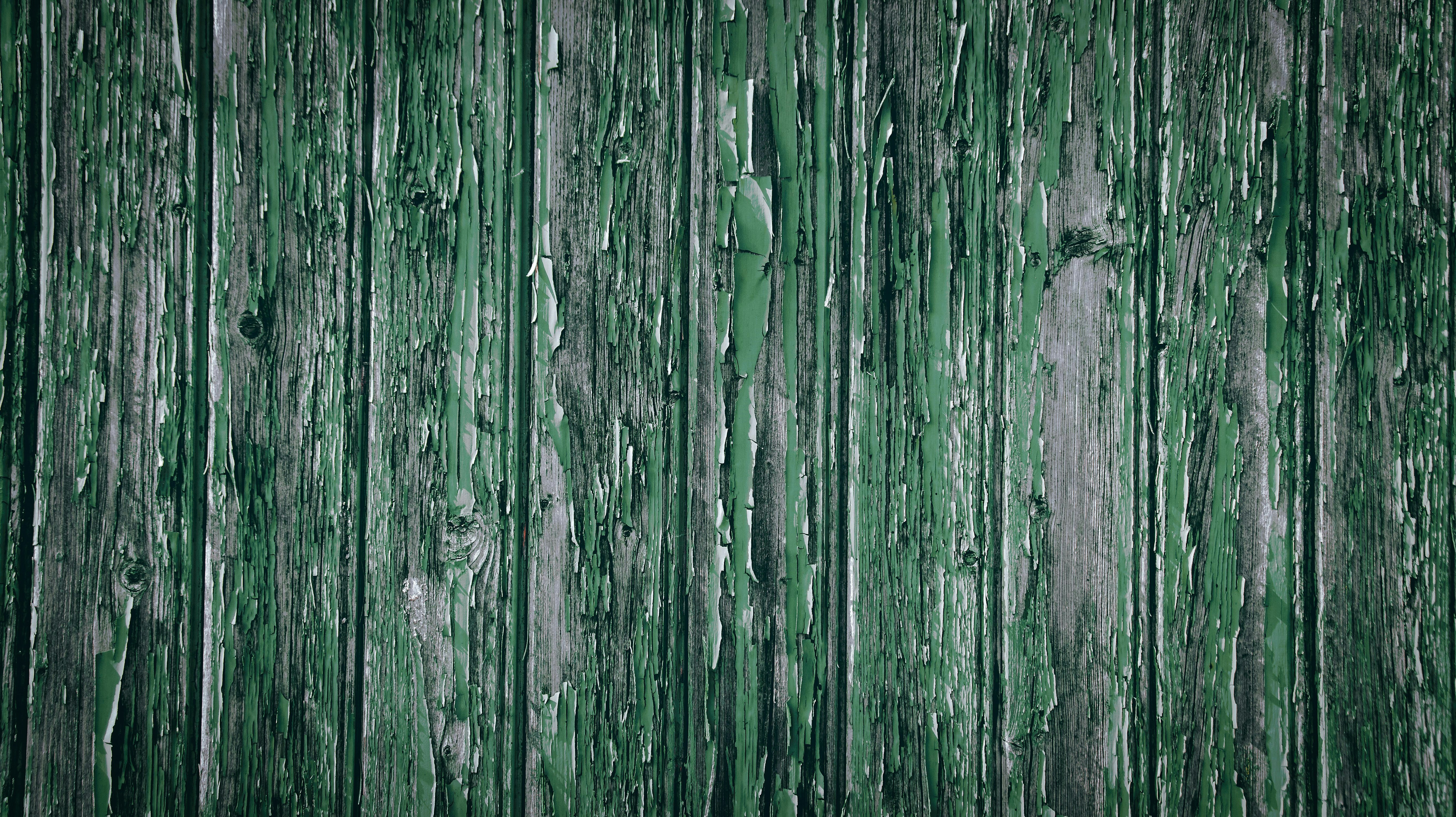Weathered green wooden planks reveal layers of history and texture, showcasing the passage of time and nature's influence.