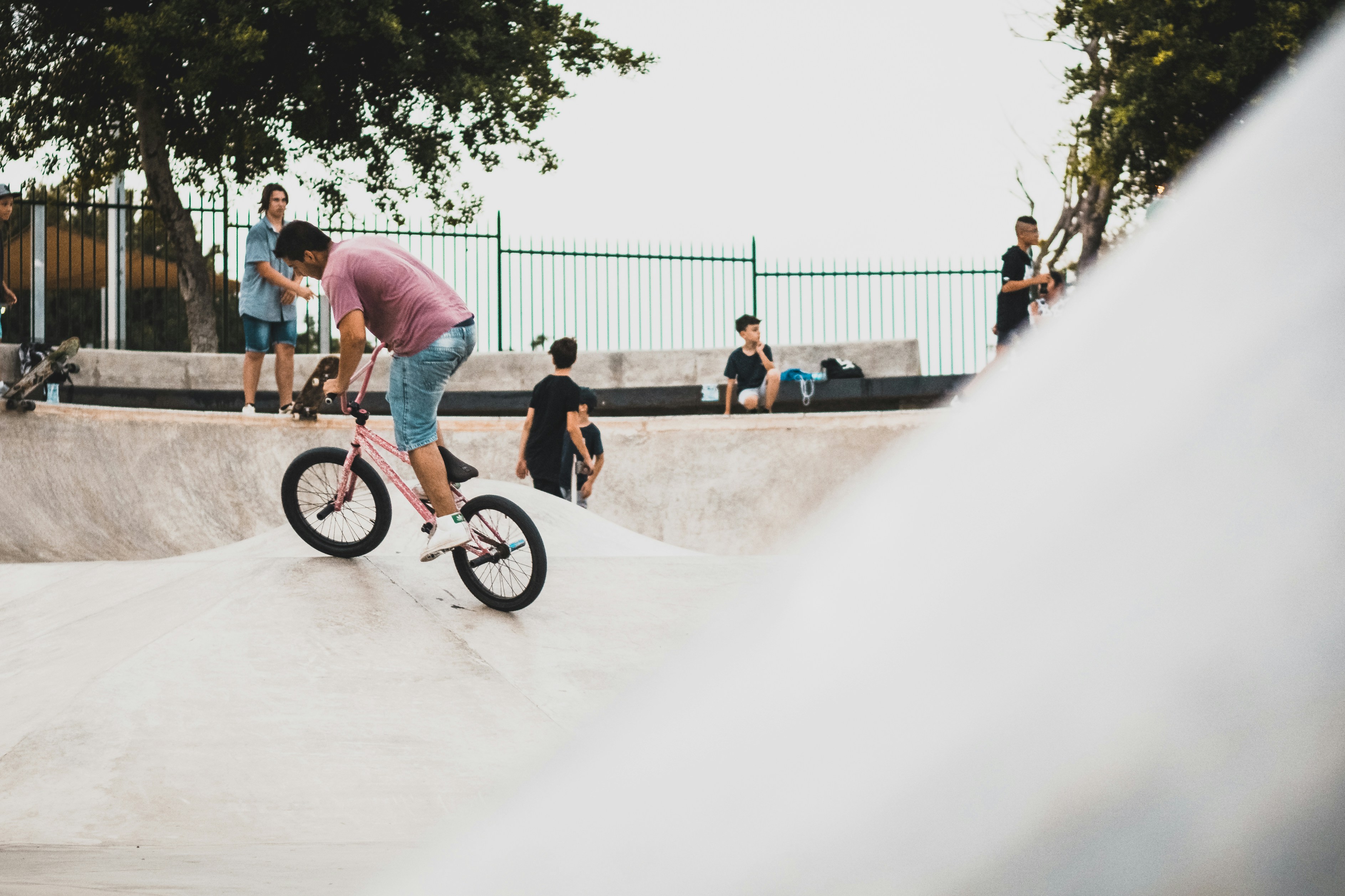 BMX rider maneuvering on curved ramp at a vibrant skatepark with spectators.