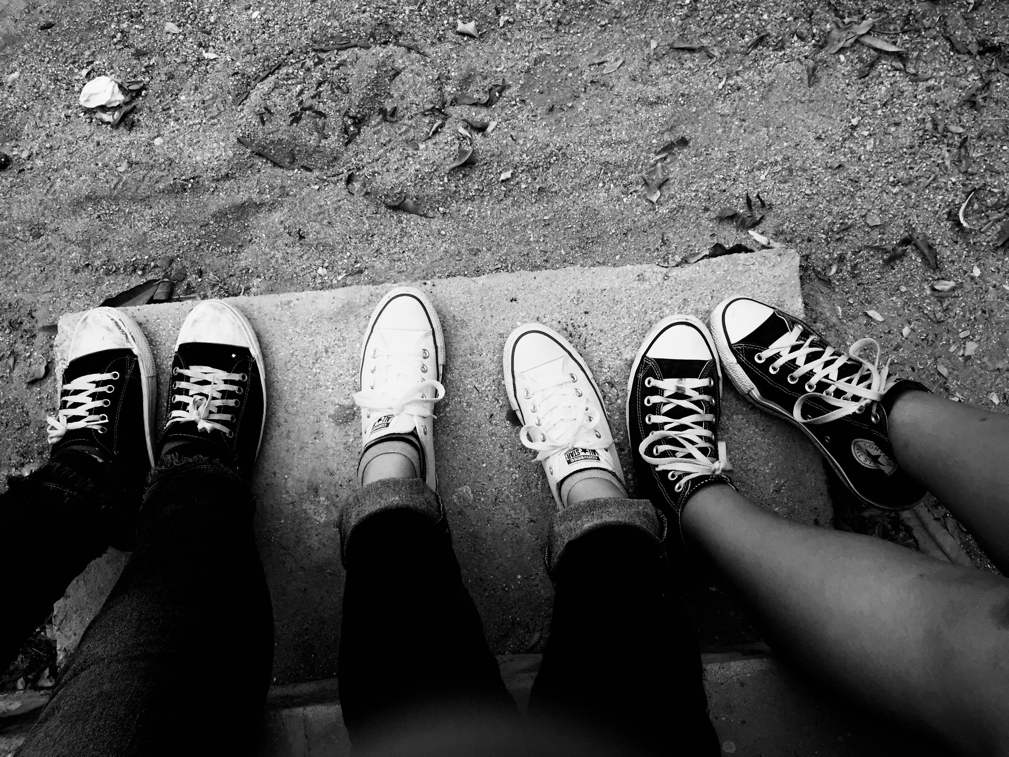 Three pairs of sneakers in varying colors and styles on a concrete step.