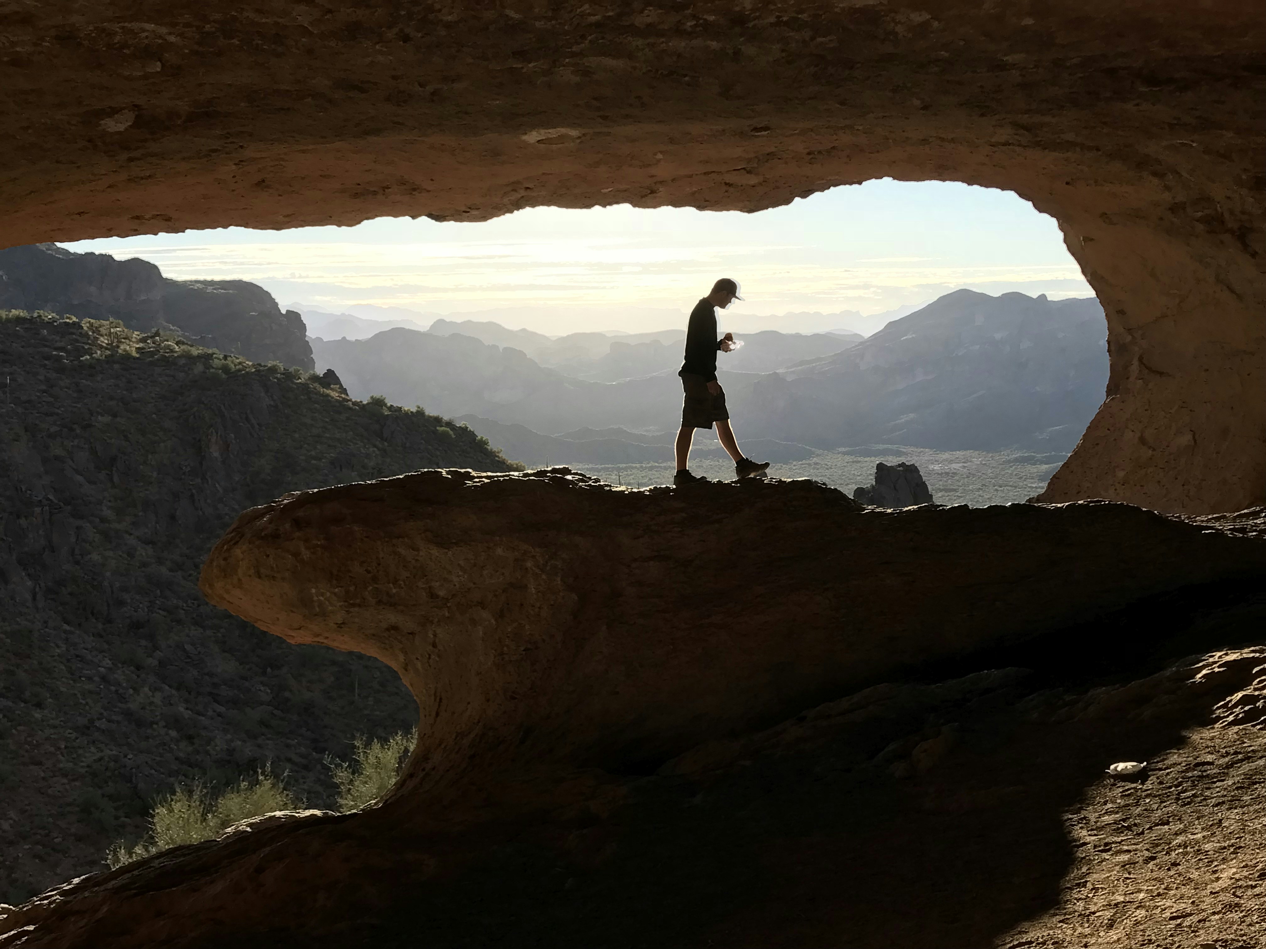 Traveler on a Sunset Vista Inside a Mountain Arch