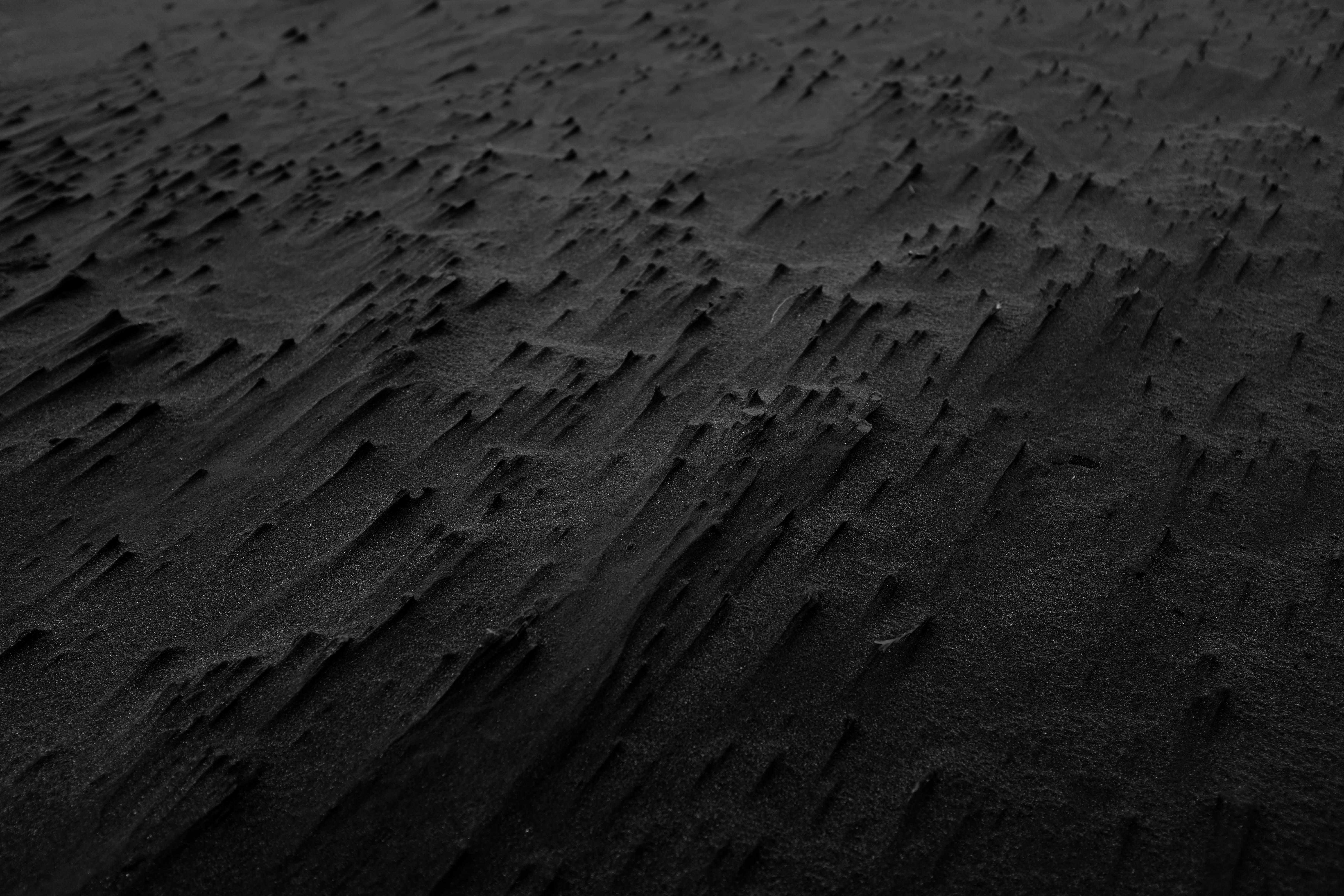 Wind-sculpted patterns on dark sand create a textured landscape.