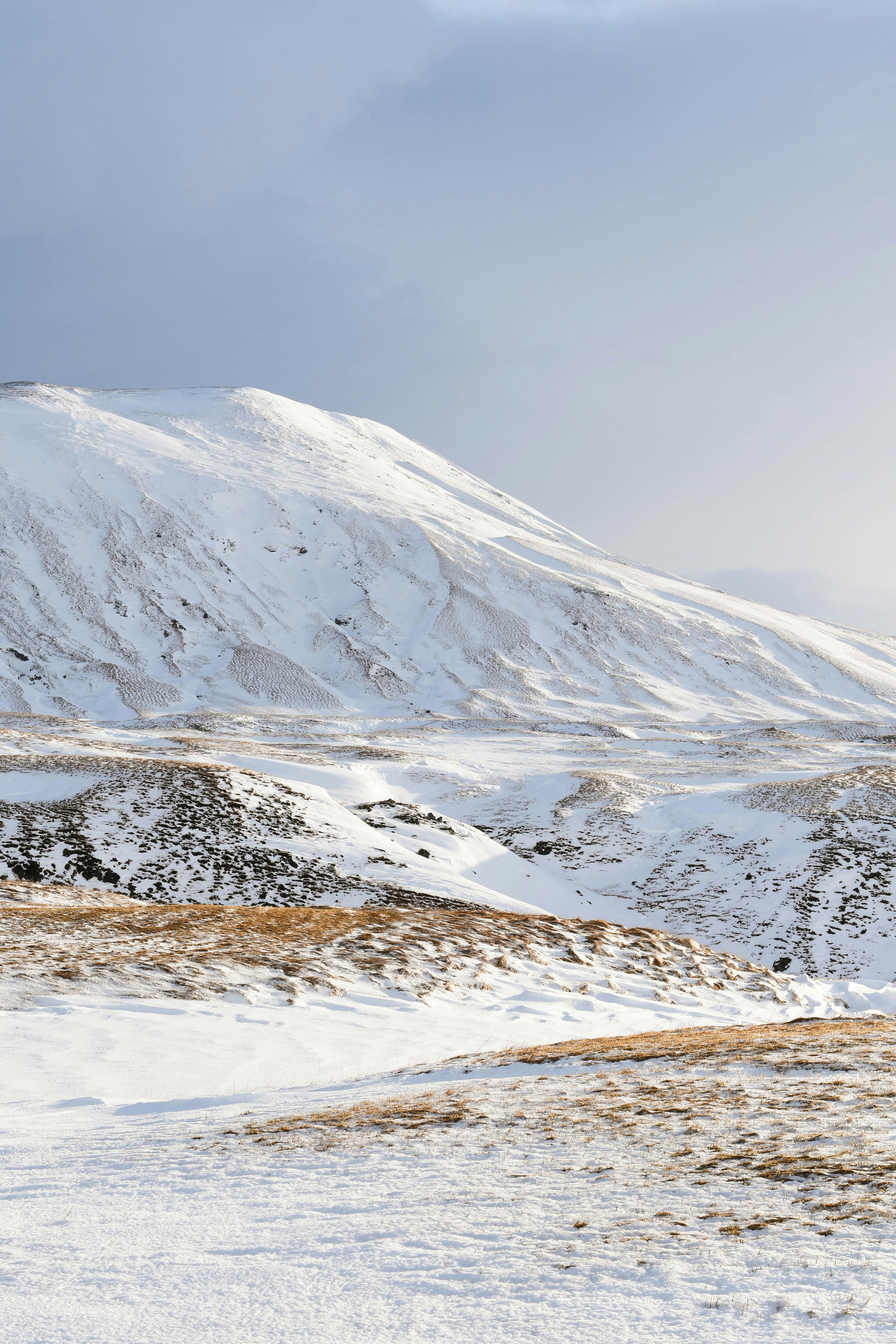 We were doing a road trip around the famous Ring Road in Iceland. We were snowed in at a farm that we were staying over at for the night. As we had to wait for the roads to be cleared we had some time to kill and went for a short walk outside. This was literally the view from the backyard of the farm. This for me was the epitome of Iceland; awe-inspiring, breathtaking and just out of this world. There’s beauty around every corner. | snow capped mountain under cloudy sky