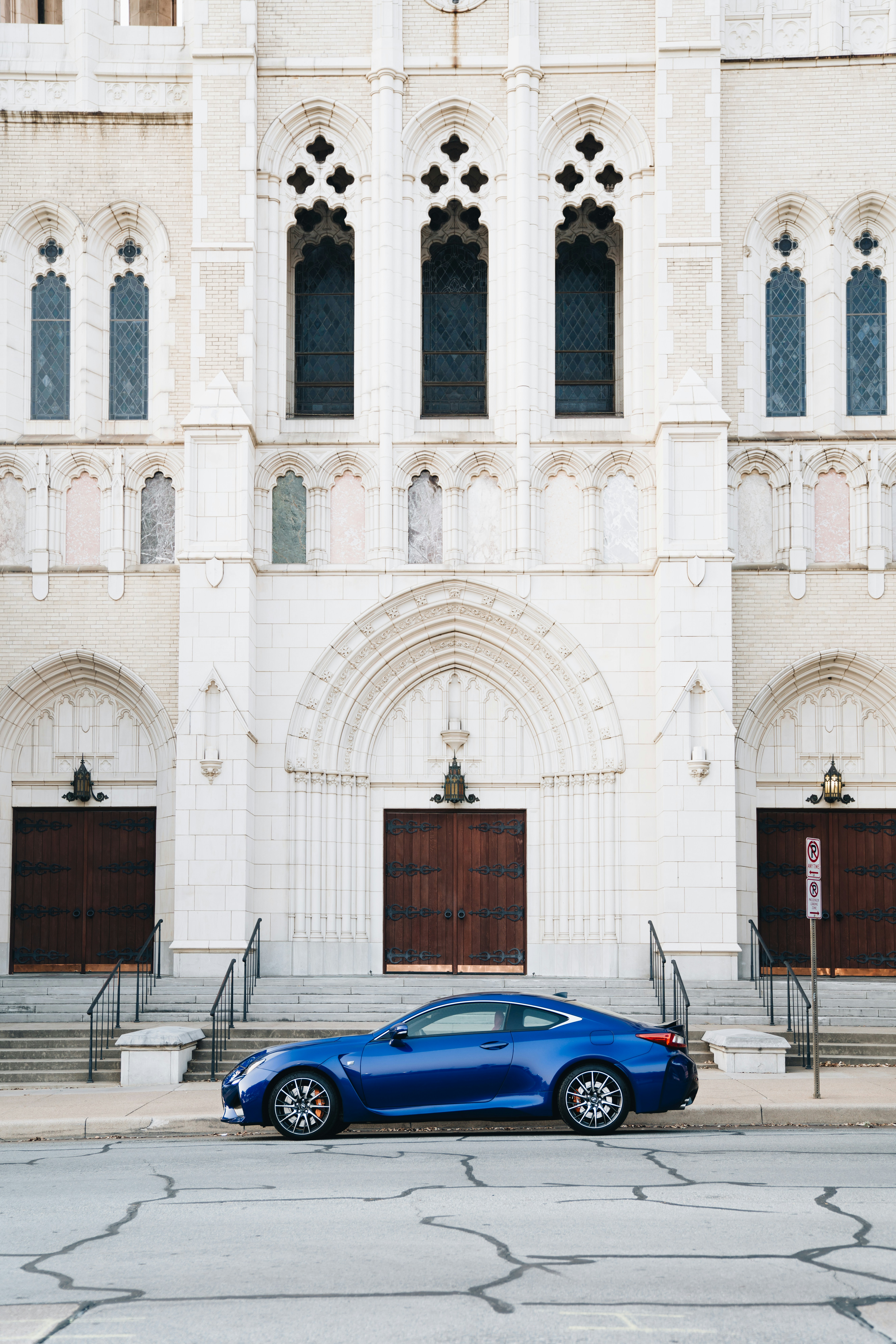 A sleek blue sports car parked in front of an ornate historic building with intricate architectural details.