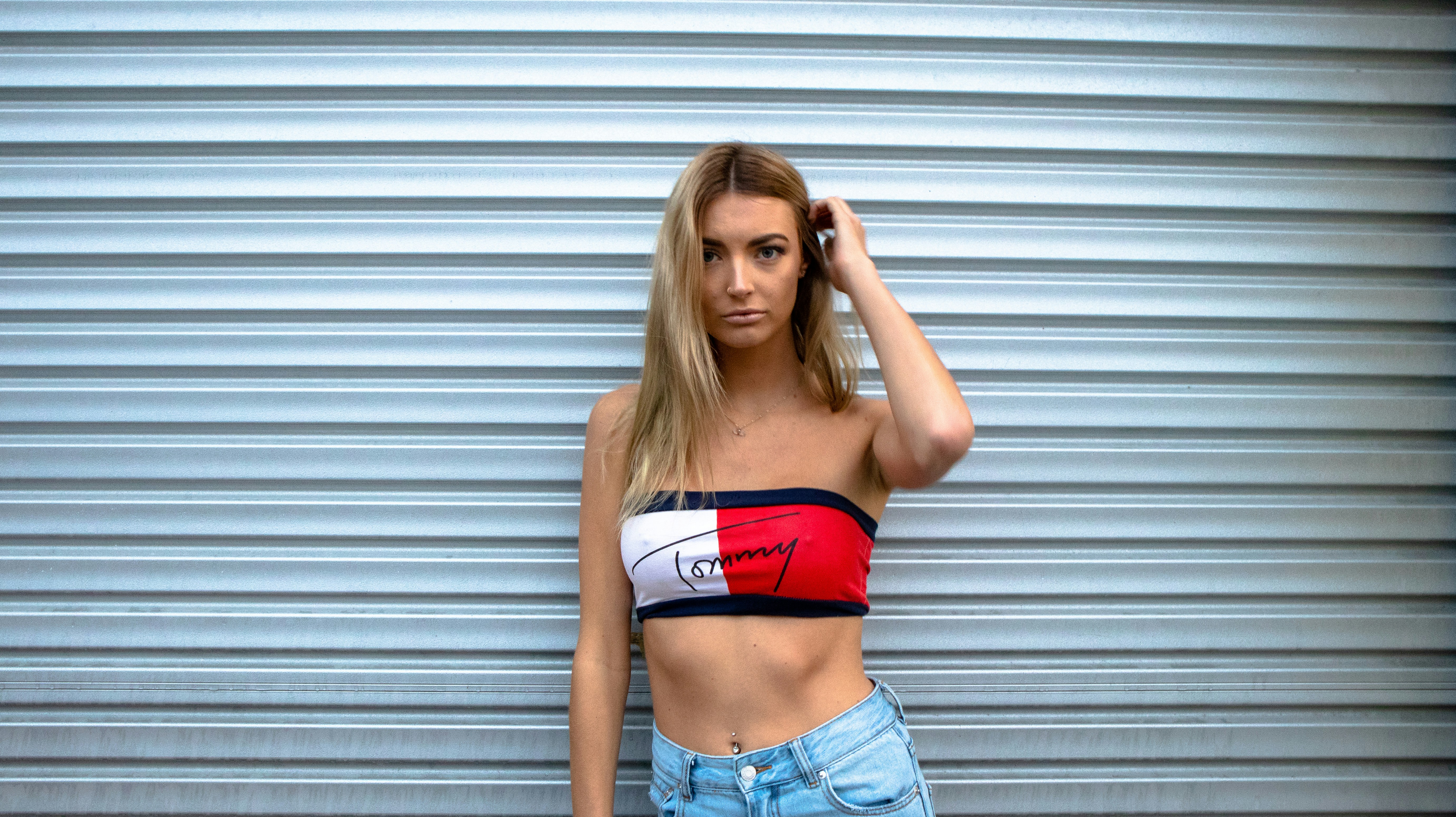 Model posing against a textured metal backdrop, showcasing a trendy crop top and denim shorts.