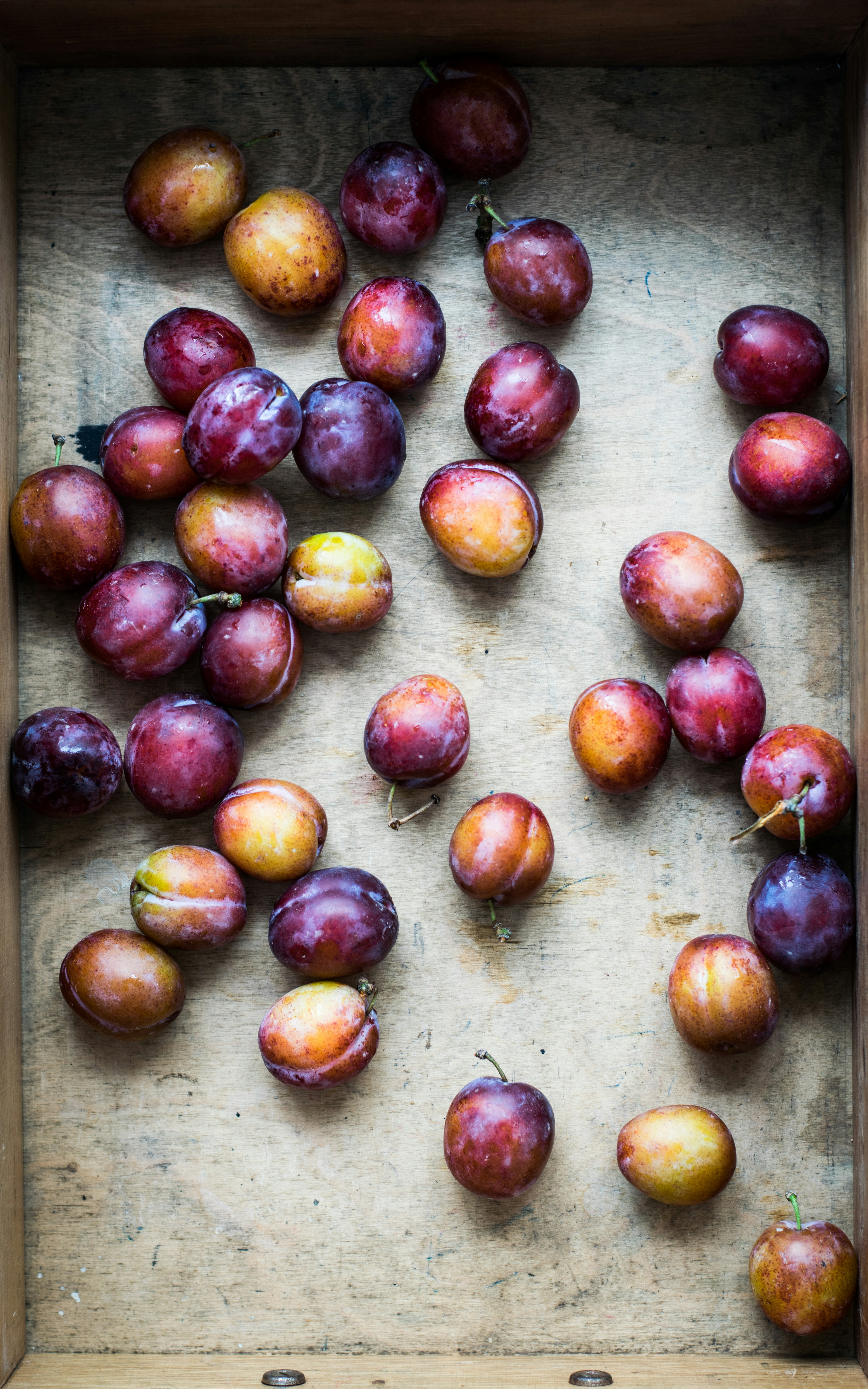 I’m charmed to see this light and color of plums! | bunch of Spanish plum on brown surface