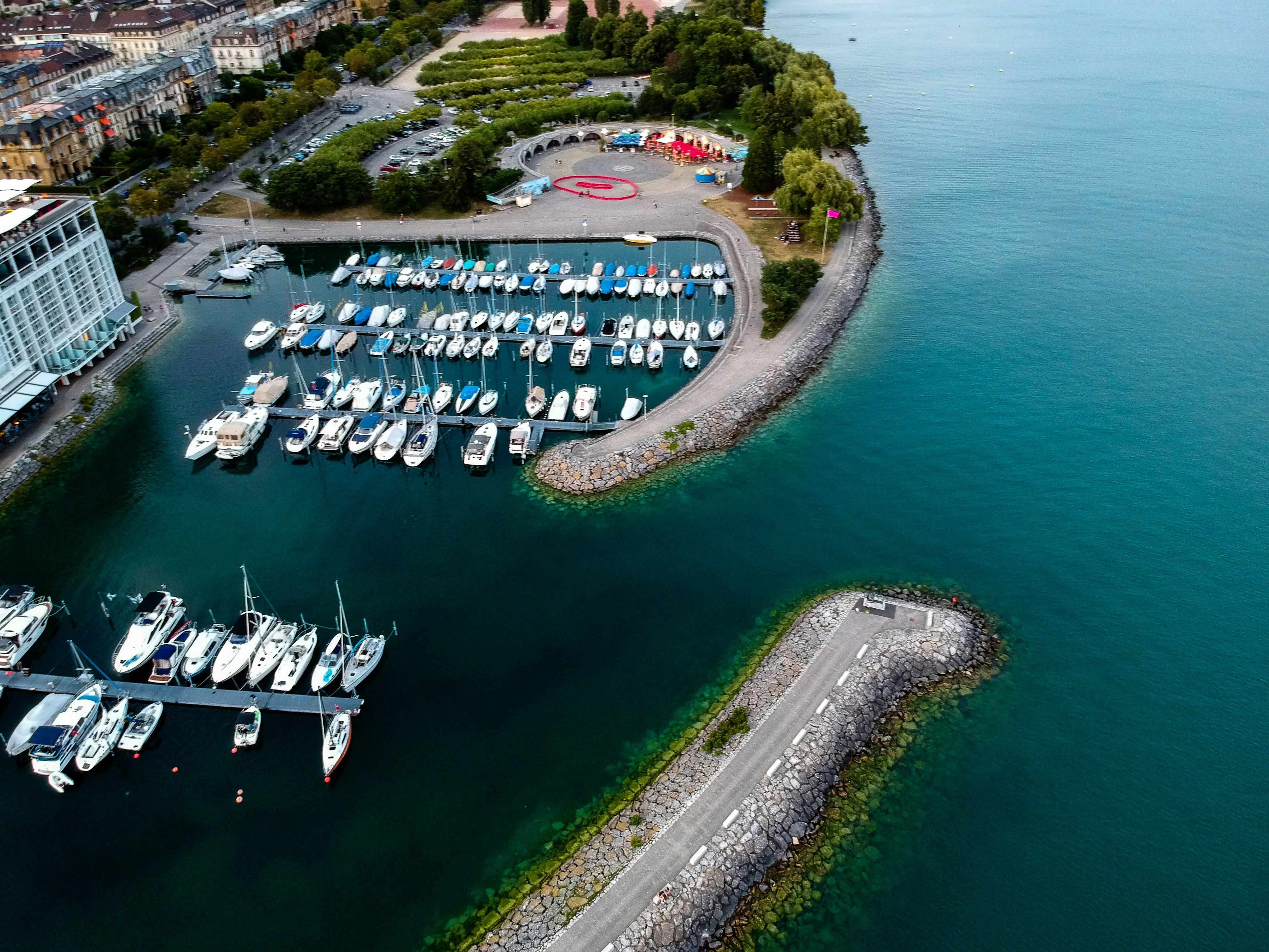 Aerial view of a marina with boats docked near a turquoise shoreline and adjacent road.