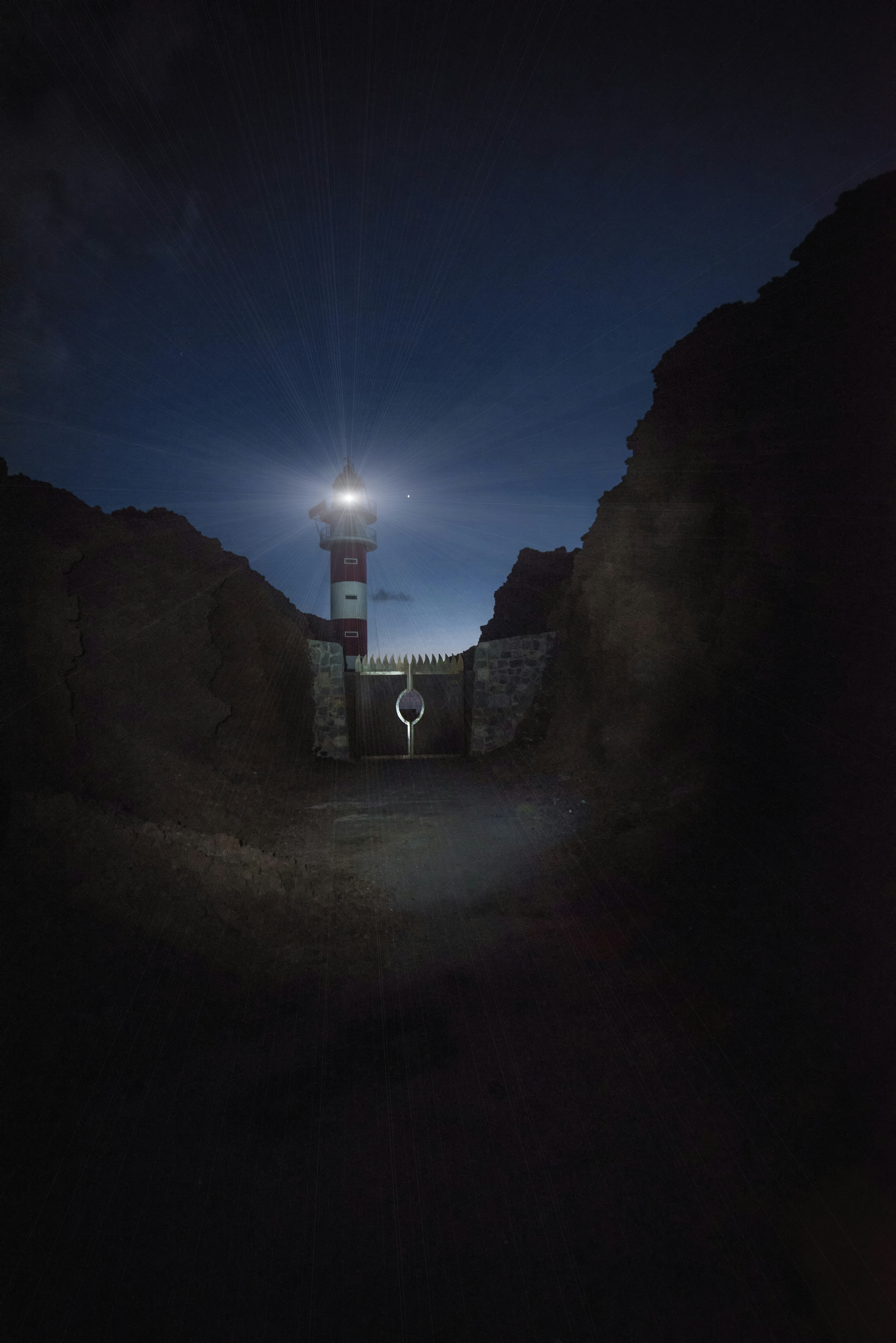 Midnight Beacon at the Gate: Lighthouse Framed by Coastal Cliffs