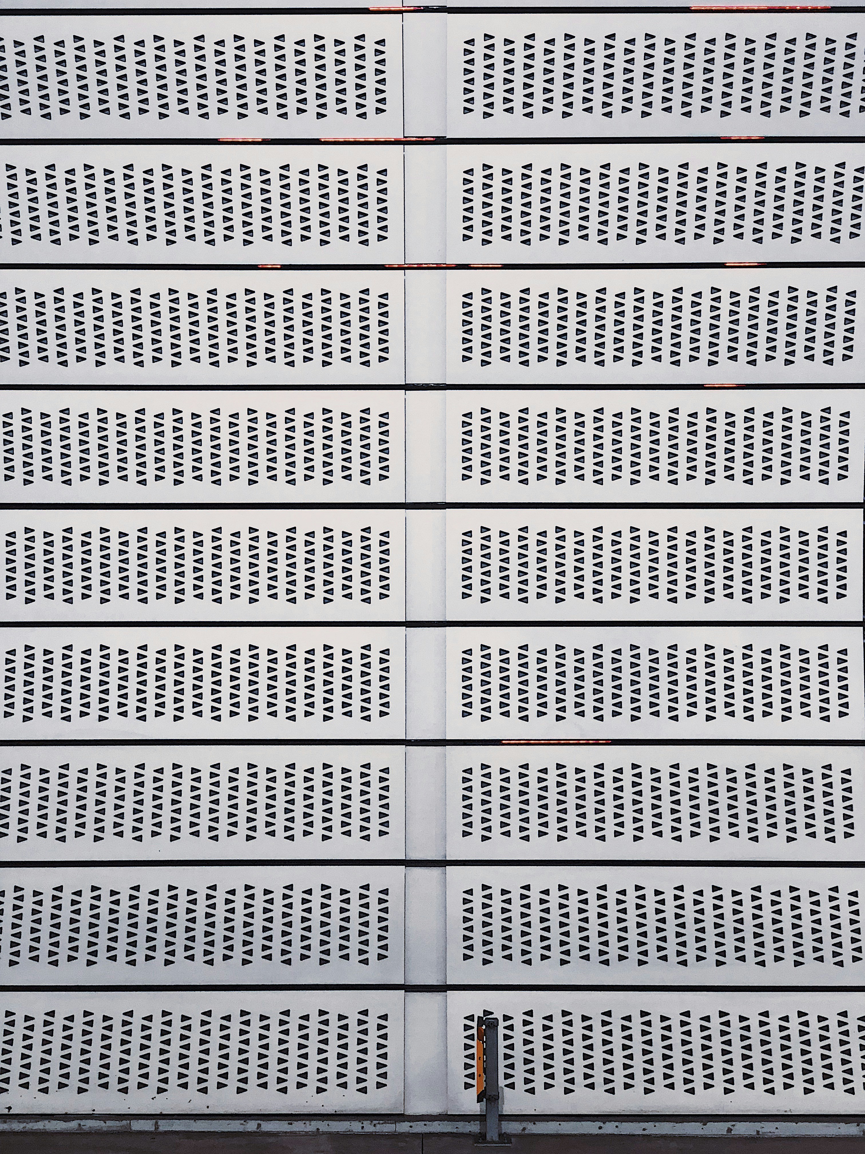 Crosshatch Silence: Grid of Vent Panels with a Lone Bolt