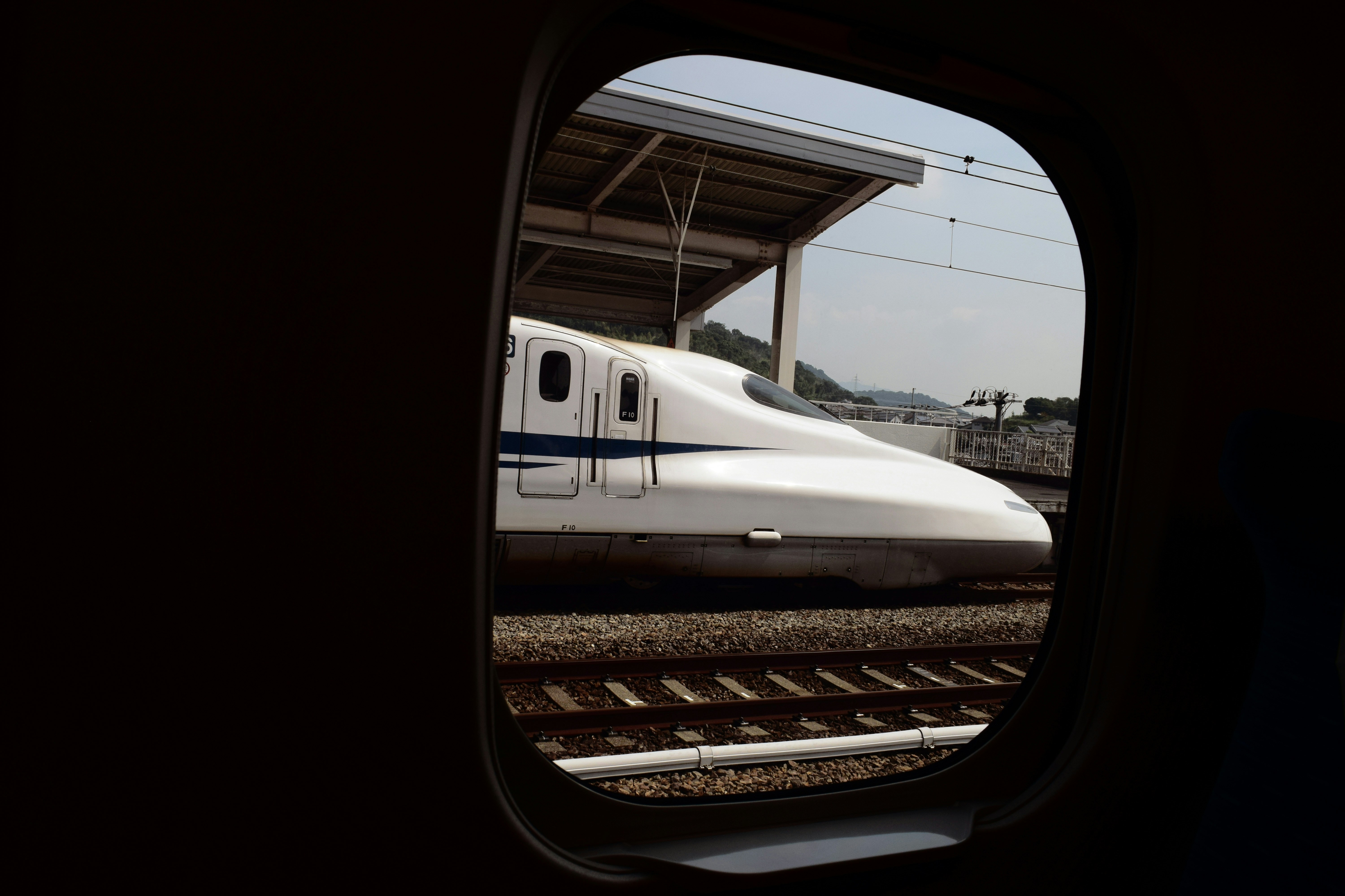 High-speed train viewed through a train window, showcasing modern transportation against a backdrop of railway tracks.