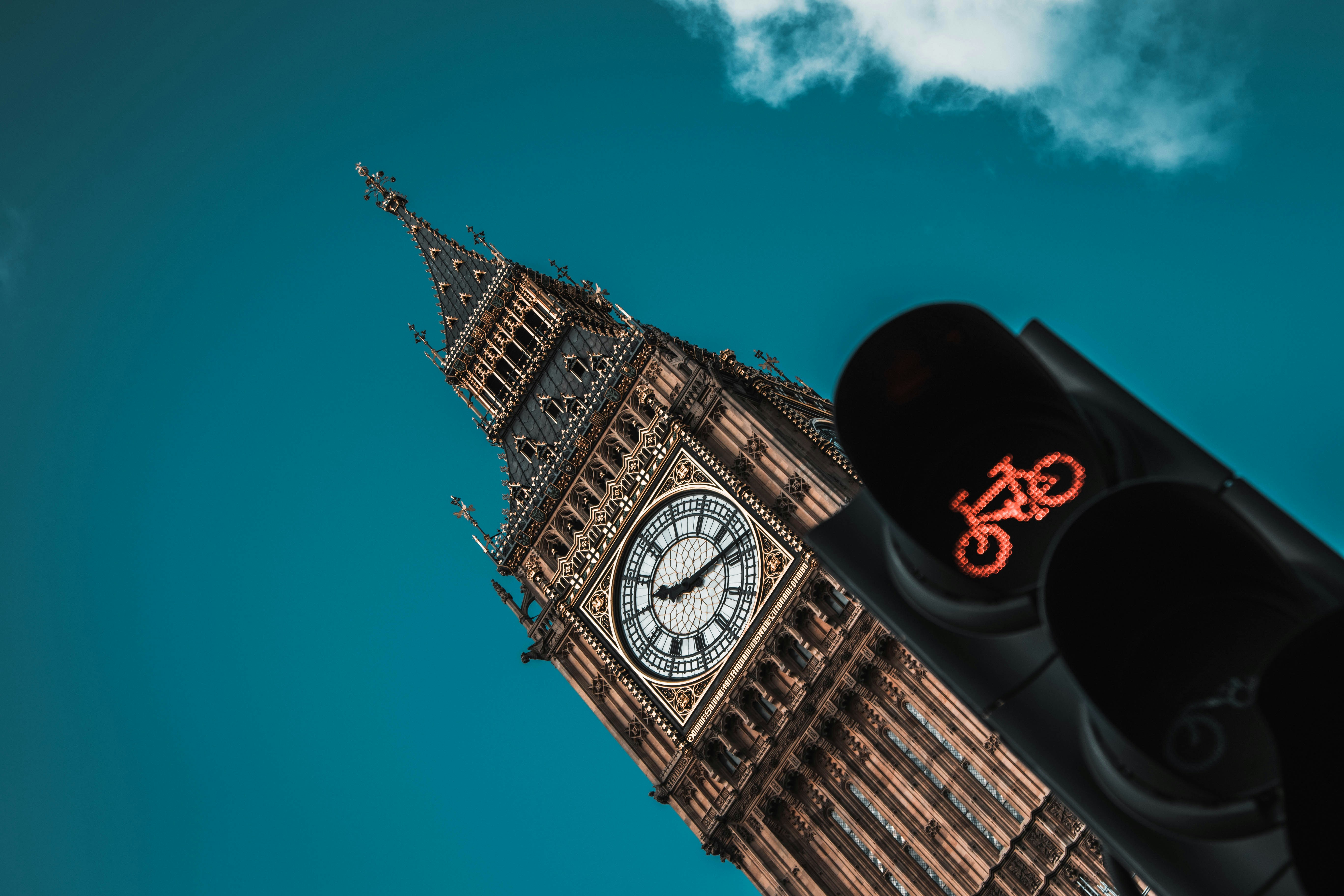 Big Ben alongside a bicycle traffic light against a vibrant blue sky.