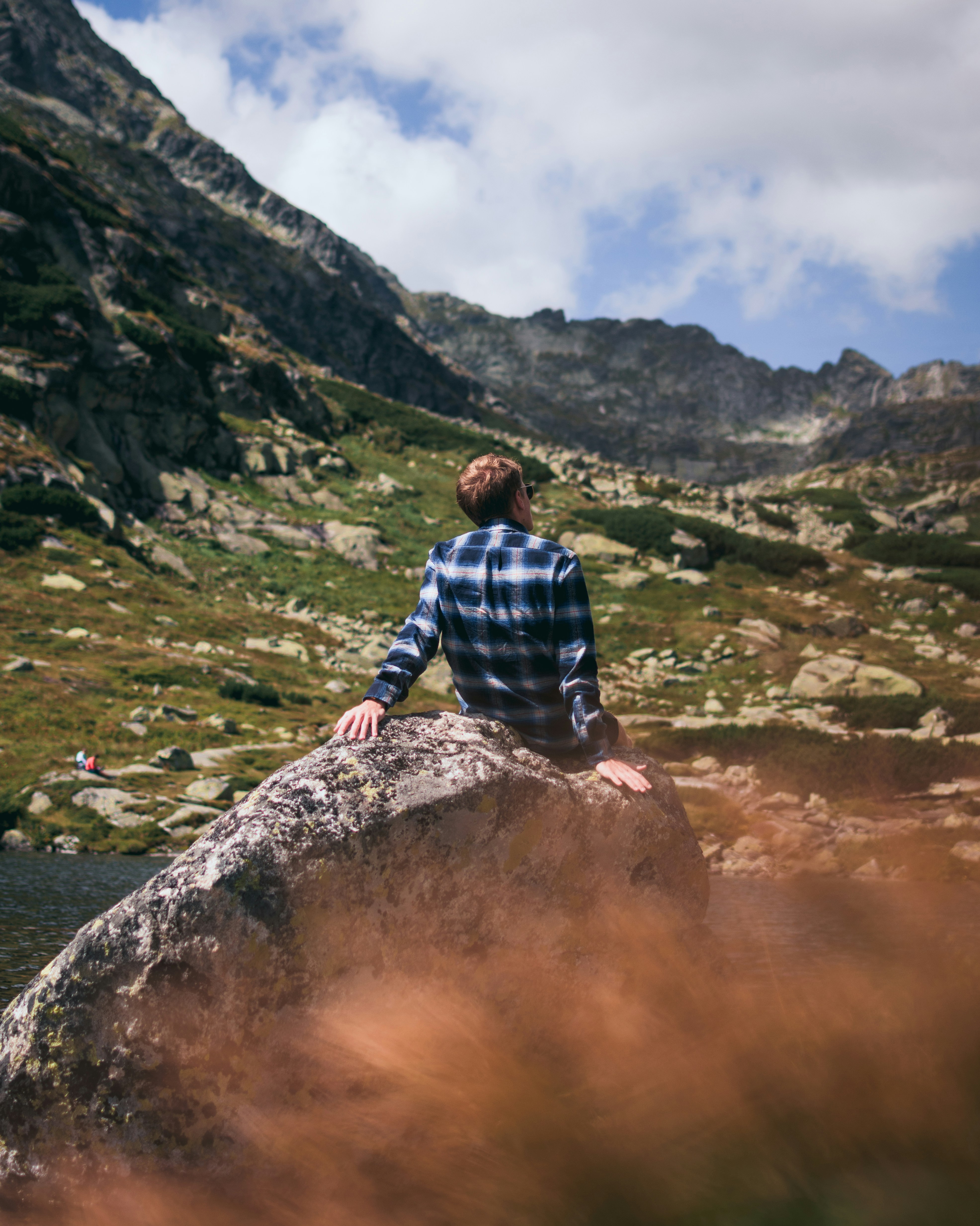 Alpine Pause on Granite: Plaid-clad hiker gazes across a sunlit valley
