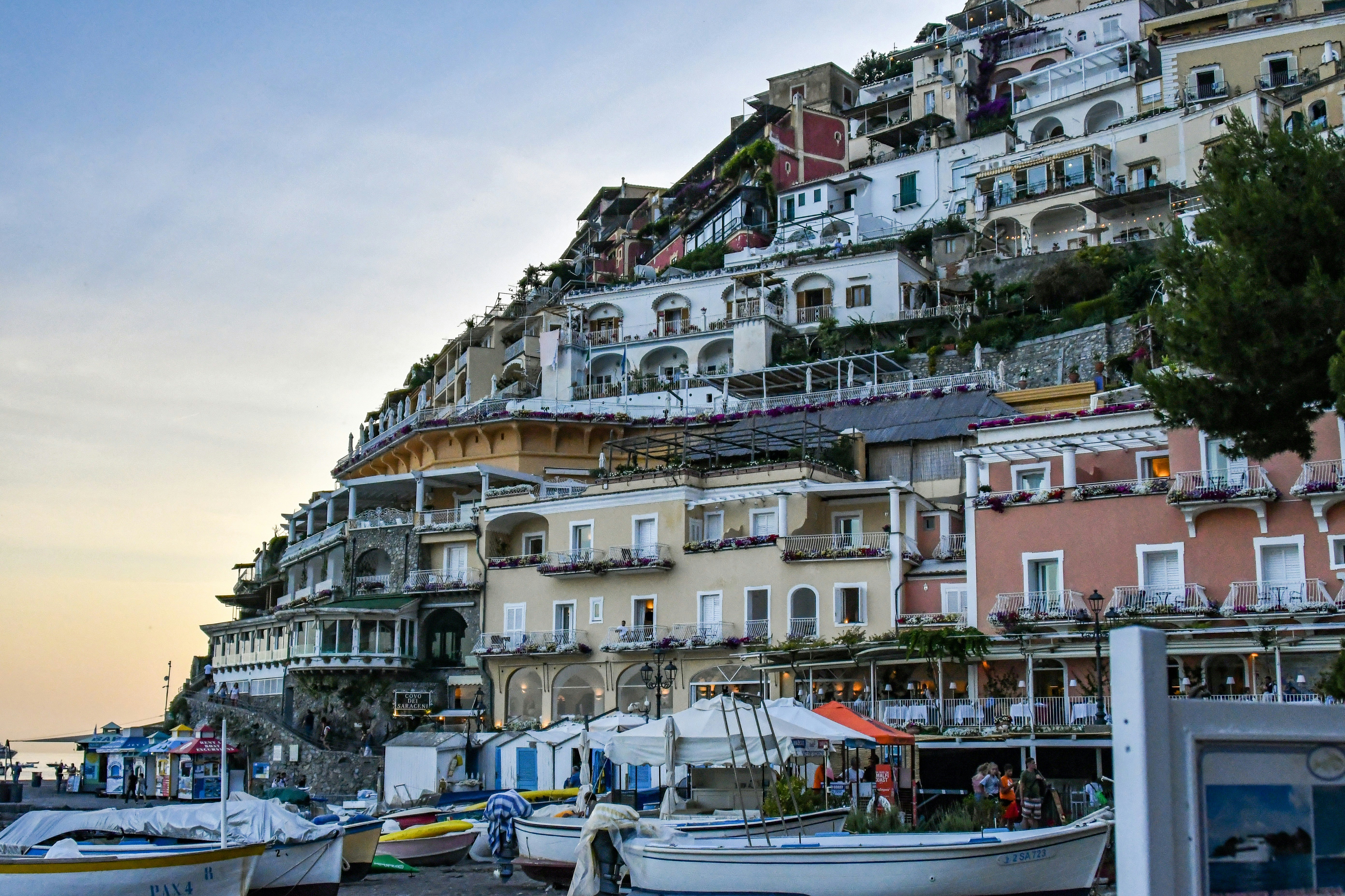 Colorful hillside buildings overlook docked boats at sunset.
