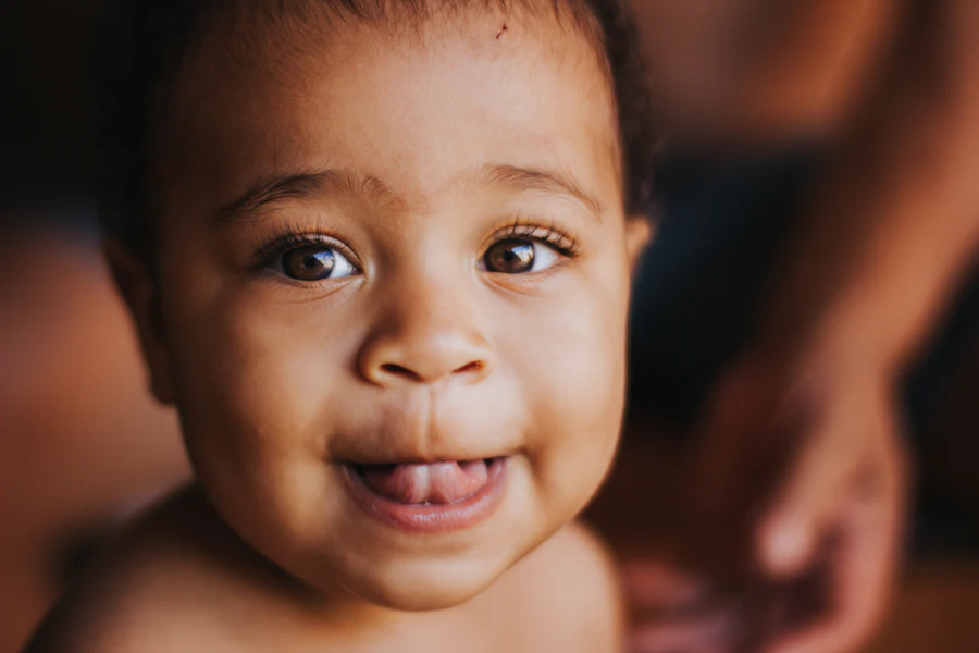 Close-up of a smiling baby with bright eyes and a playful expression, capturing a moment of joy and innocence.