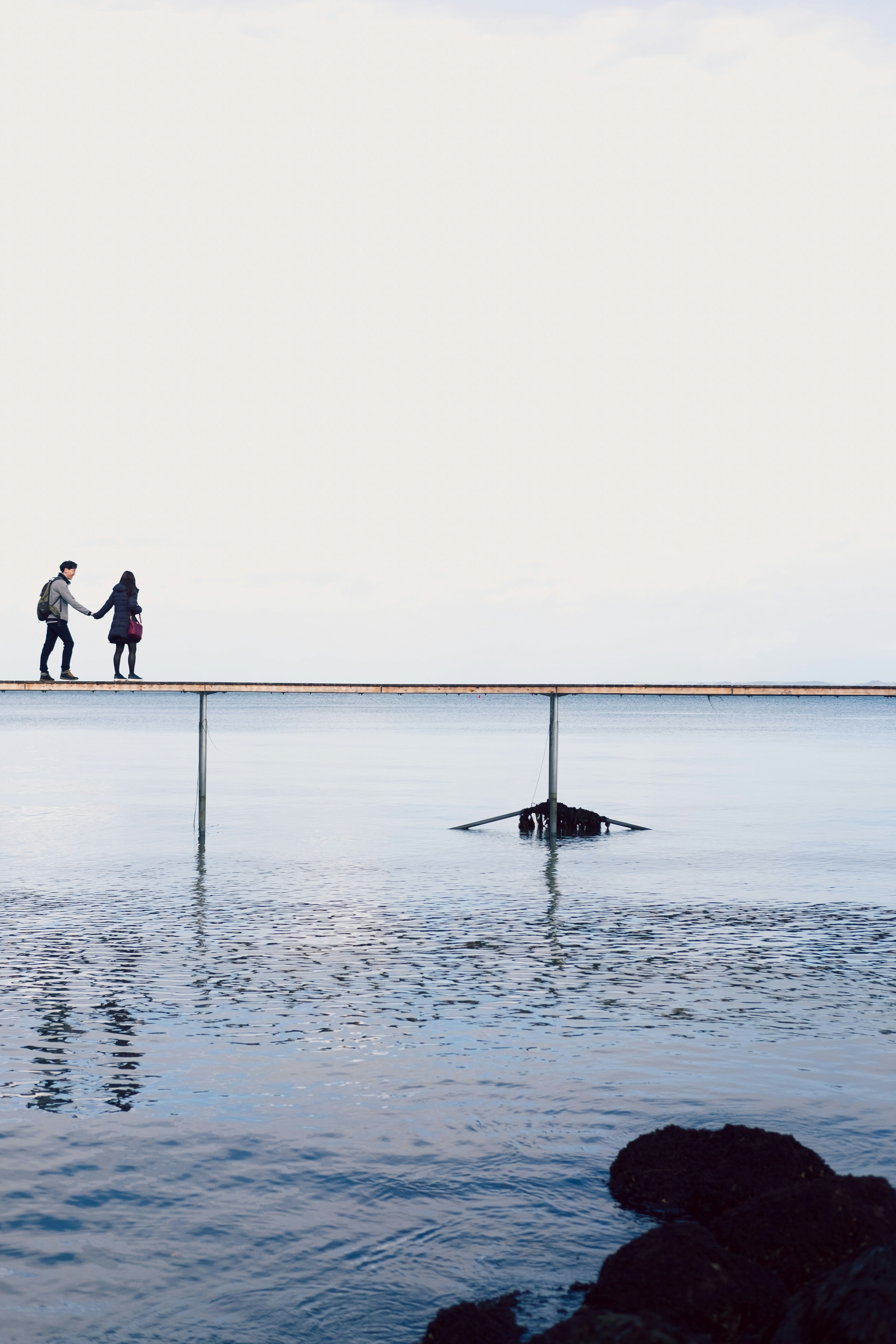 Edge of Light: Two Figures on a Narrow Pier Over a Quiet Sea