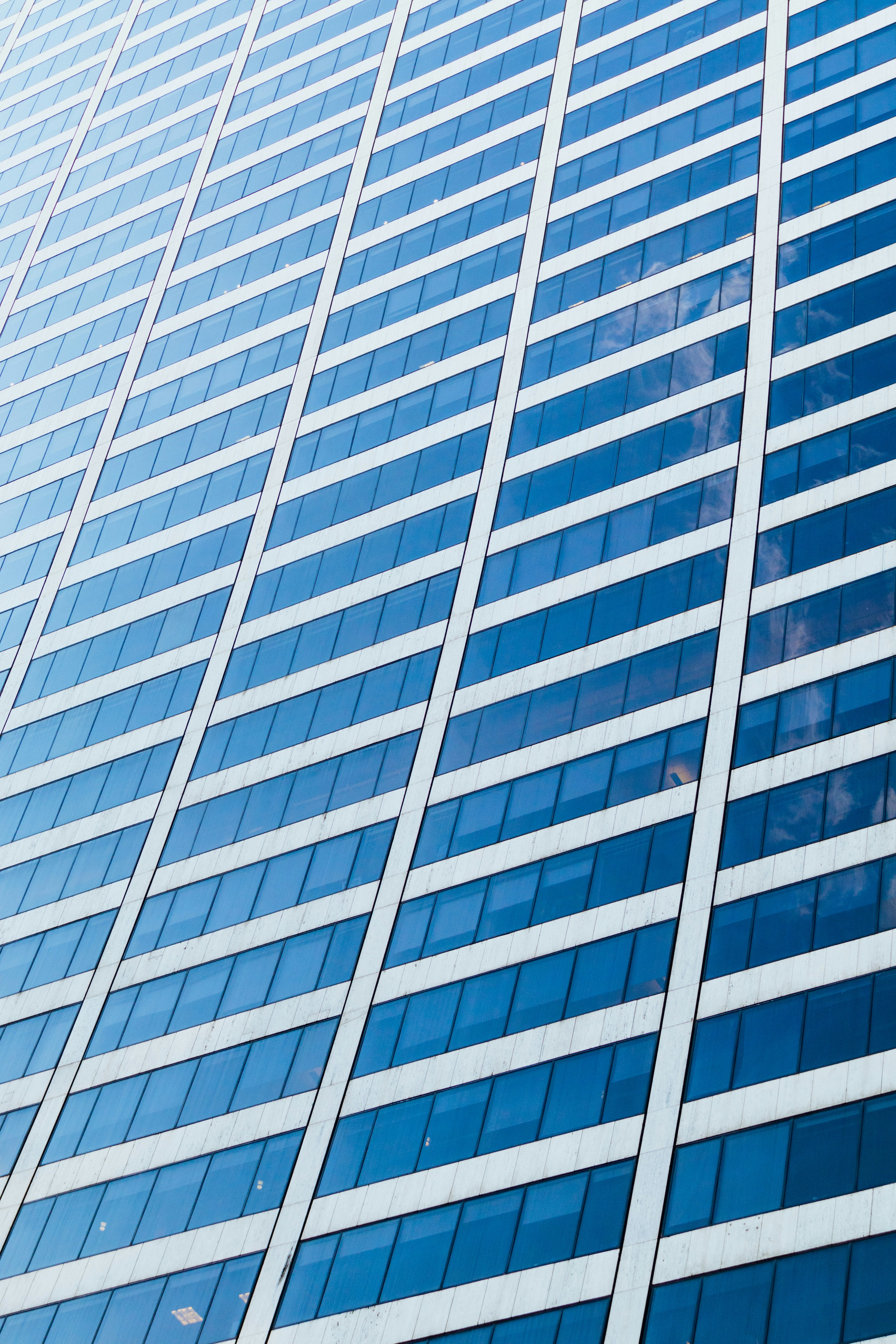 Tall glass building with reflective blue windows in a diagonal pattern.