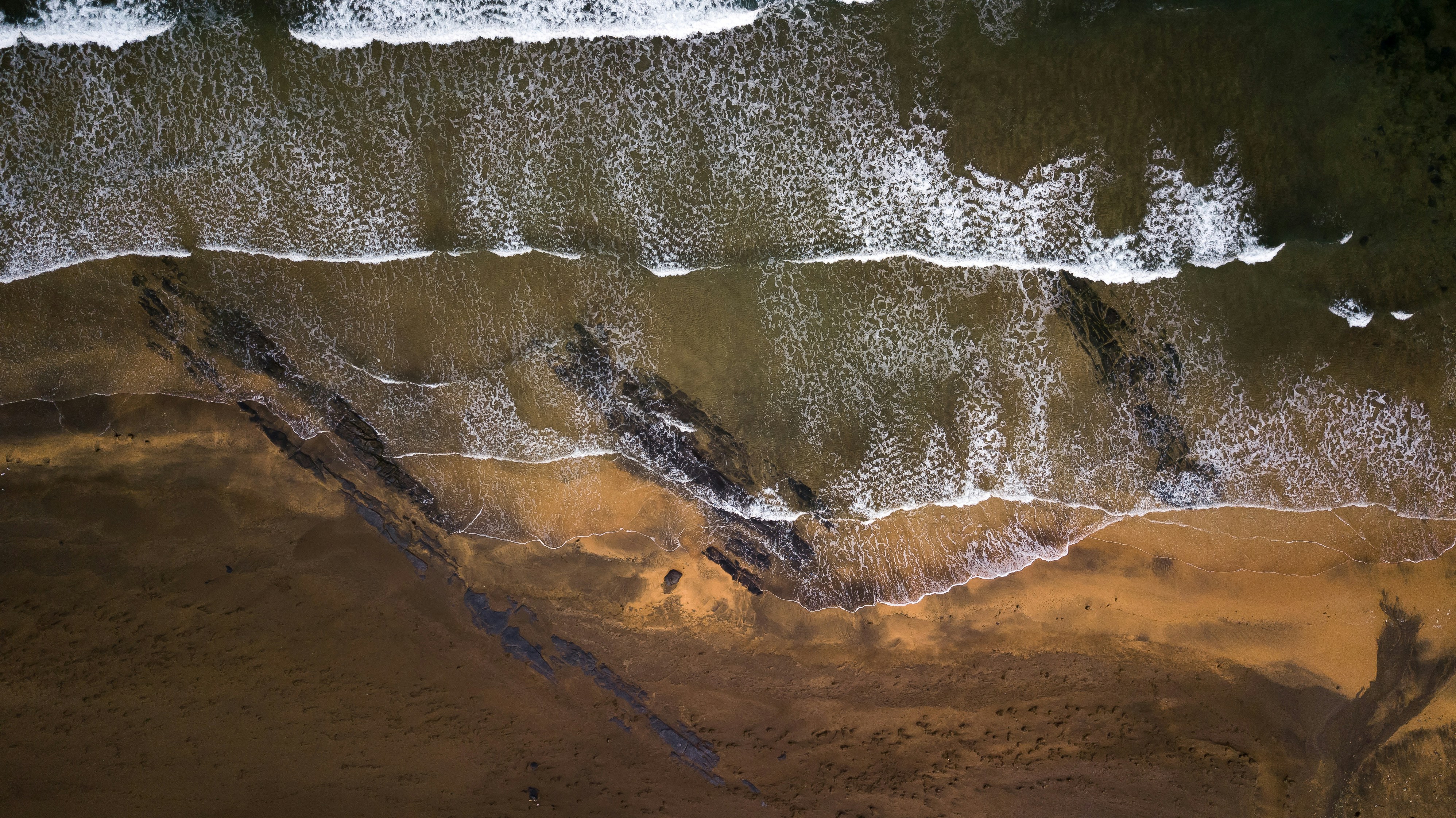 Waves gently caressing the shoreline, revealing intricate patterns on wet sand. The interplay of water and land showcases the dynamic beauty of coastal landscapes.