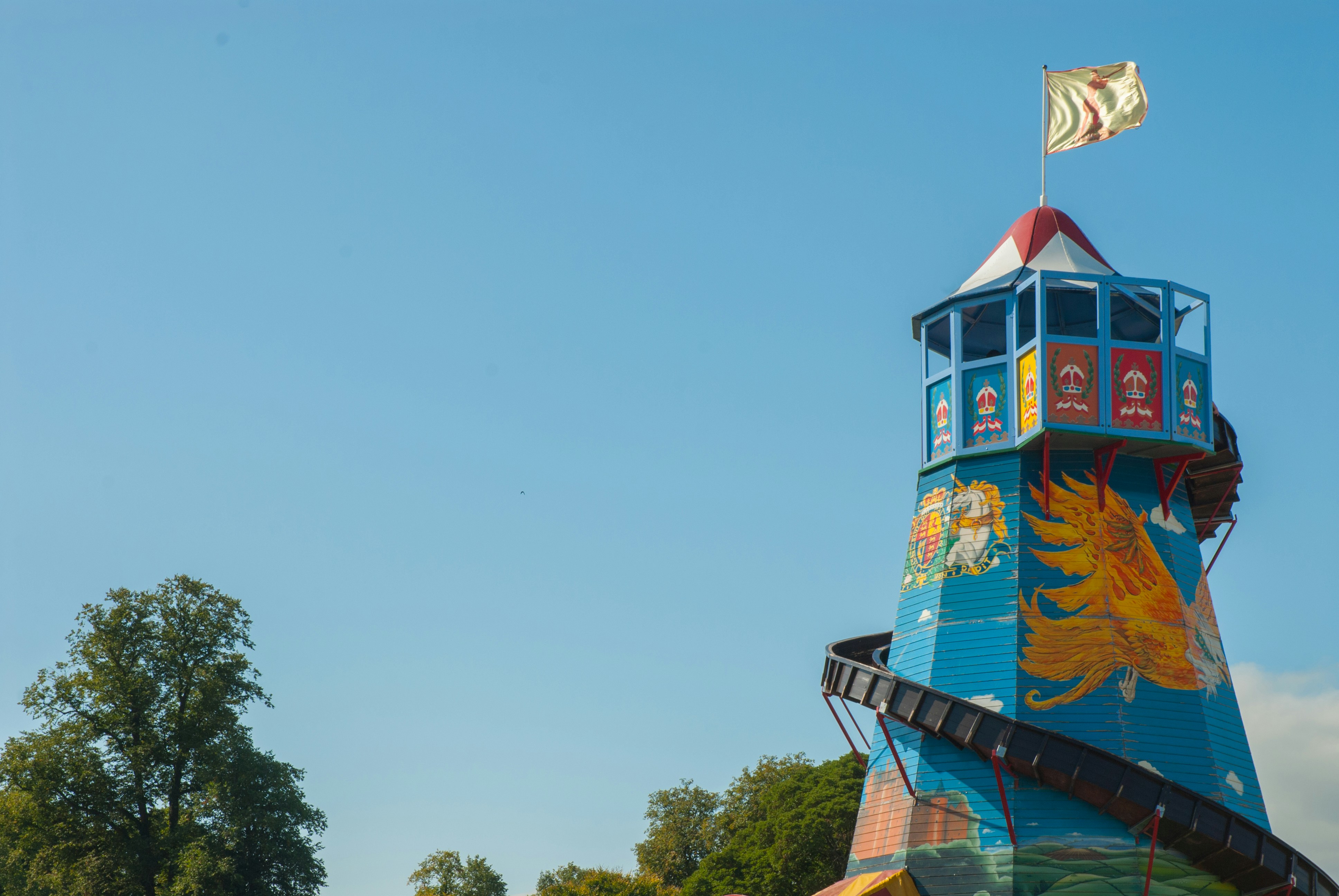 A whimsical watchtower adorned with vivid murals, featuring a flag fluttering at its peak against a clear blue sky.