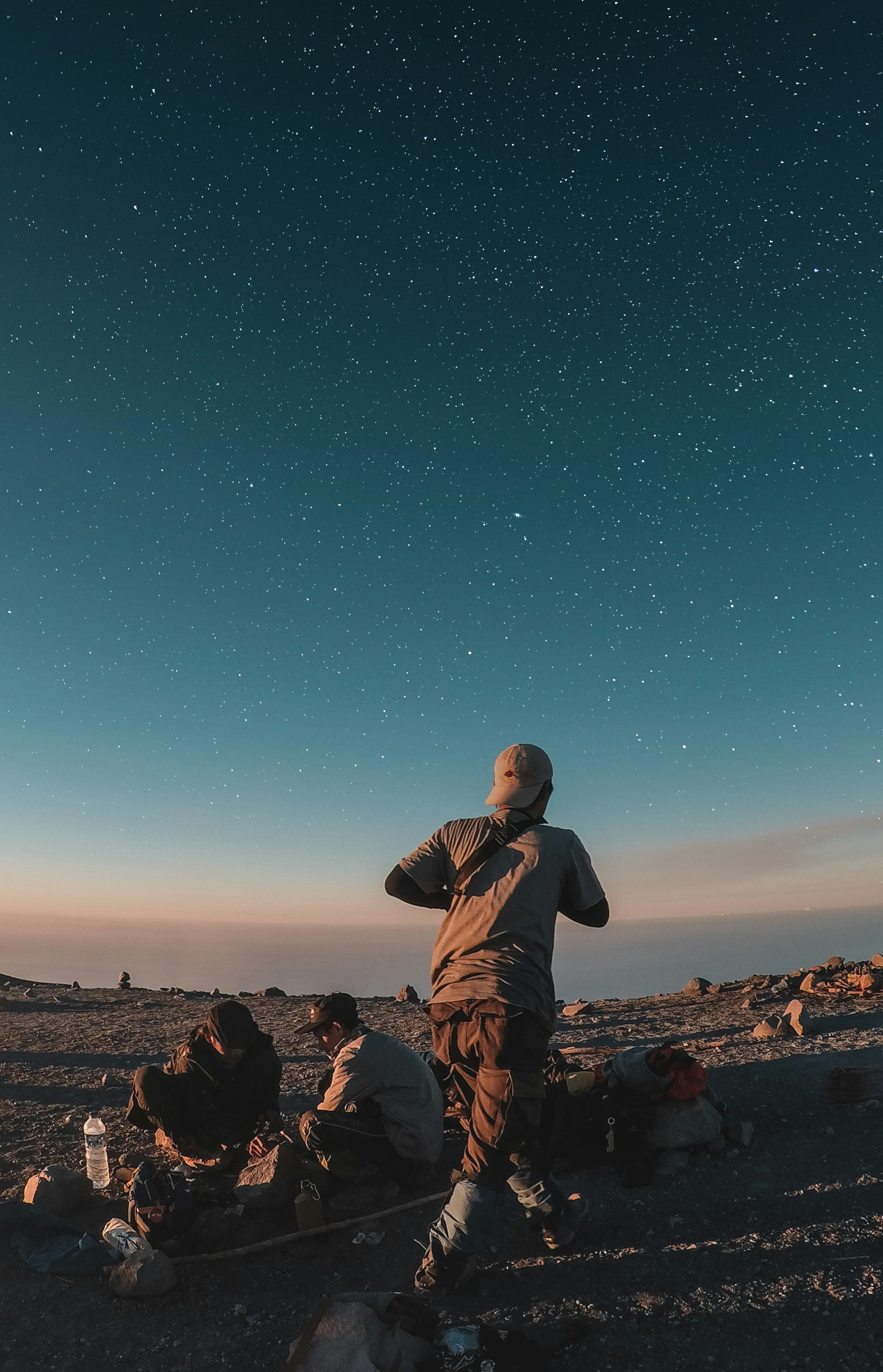 Man running behind two men sitting on rock photo – Free People Image on ...