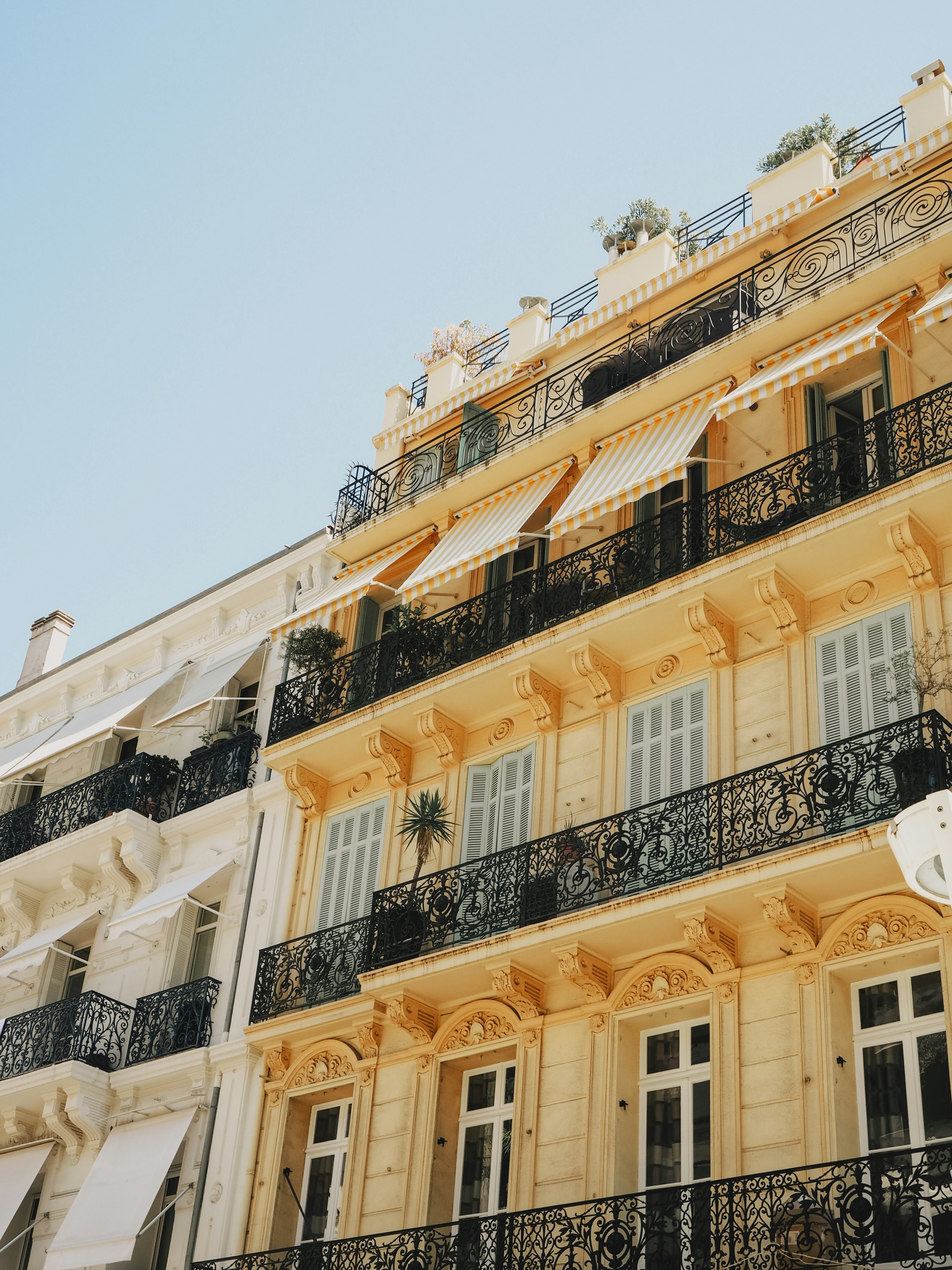 Elegant buildings with intricate balconies and awnings against a clear blue sky.