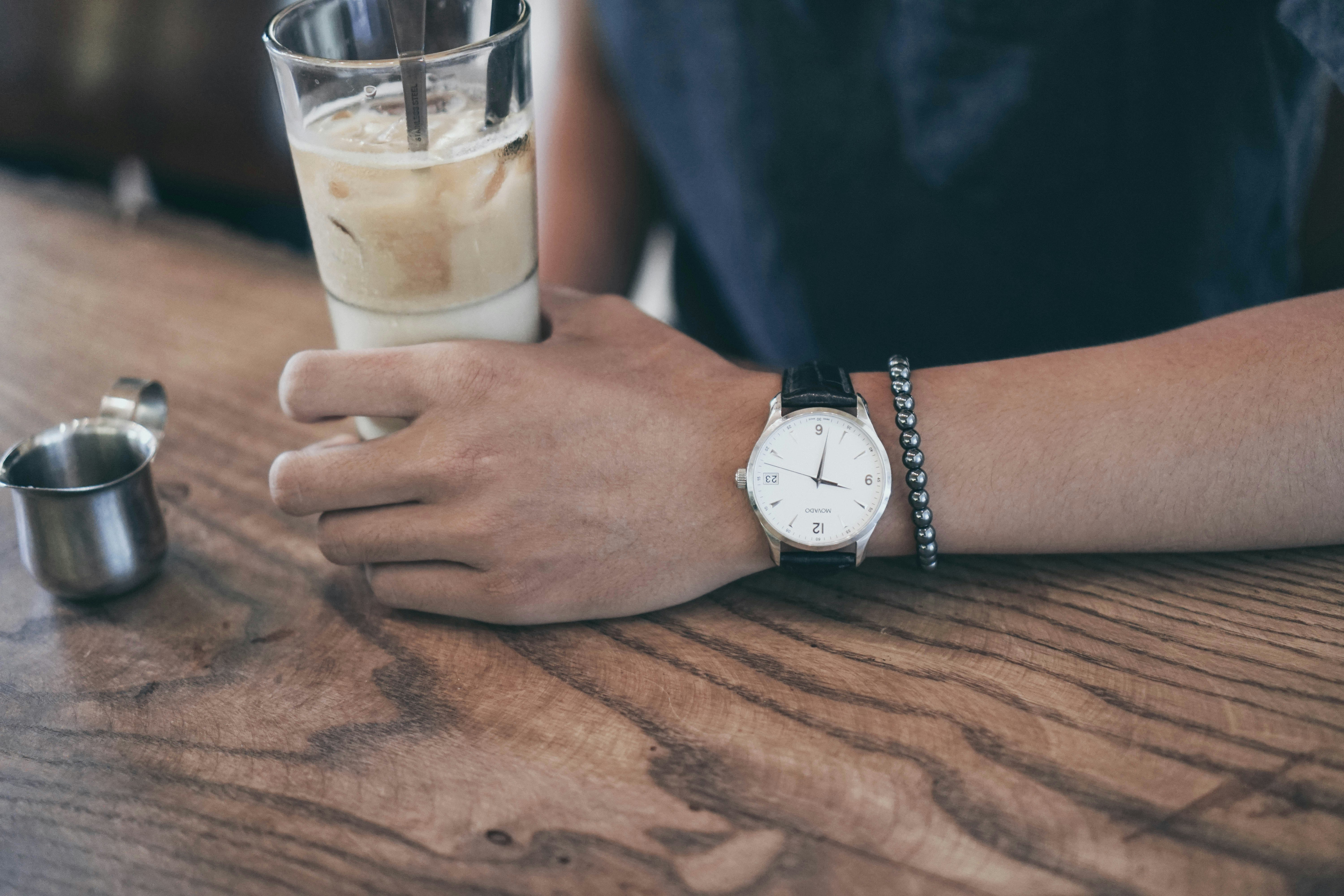 Quiet Hour at the Counter: Wristwatch, Iced Coffee, and Wooden Table