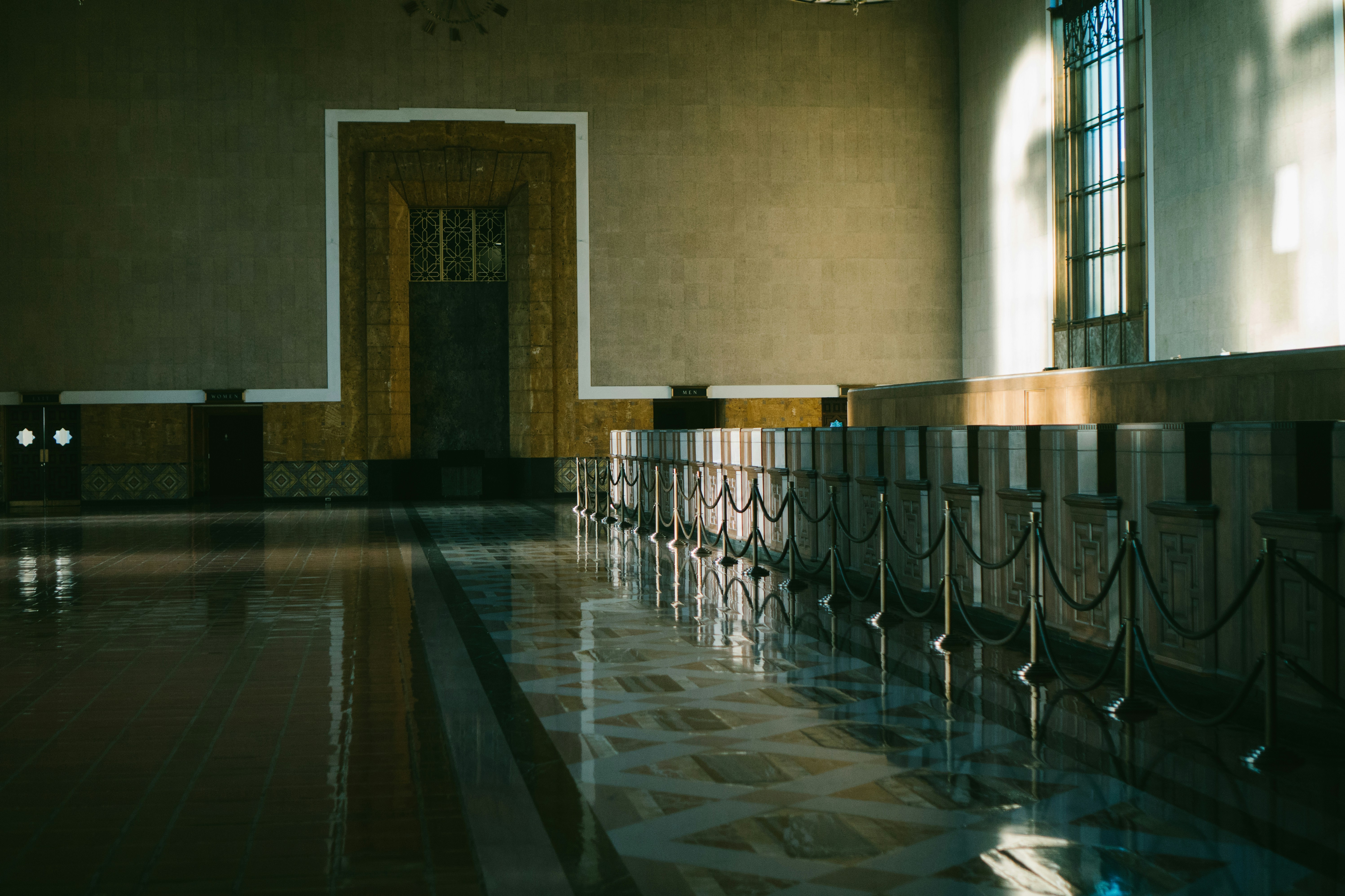 Sunlit hallway with a row of chairs and intricate floor patterns.