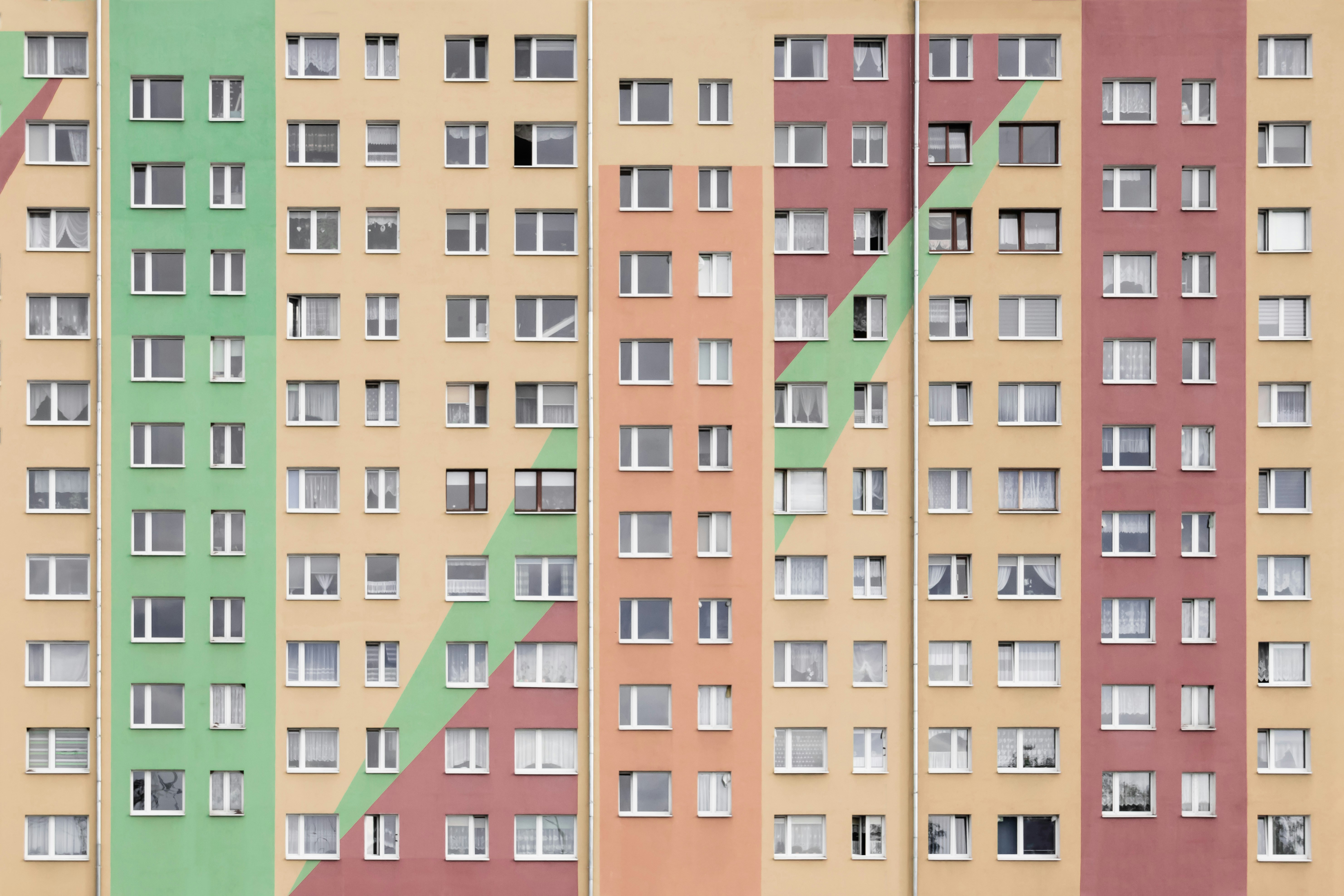 Colorful geometric facade of an apartment building with rows of windows and diagonal stripes.