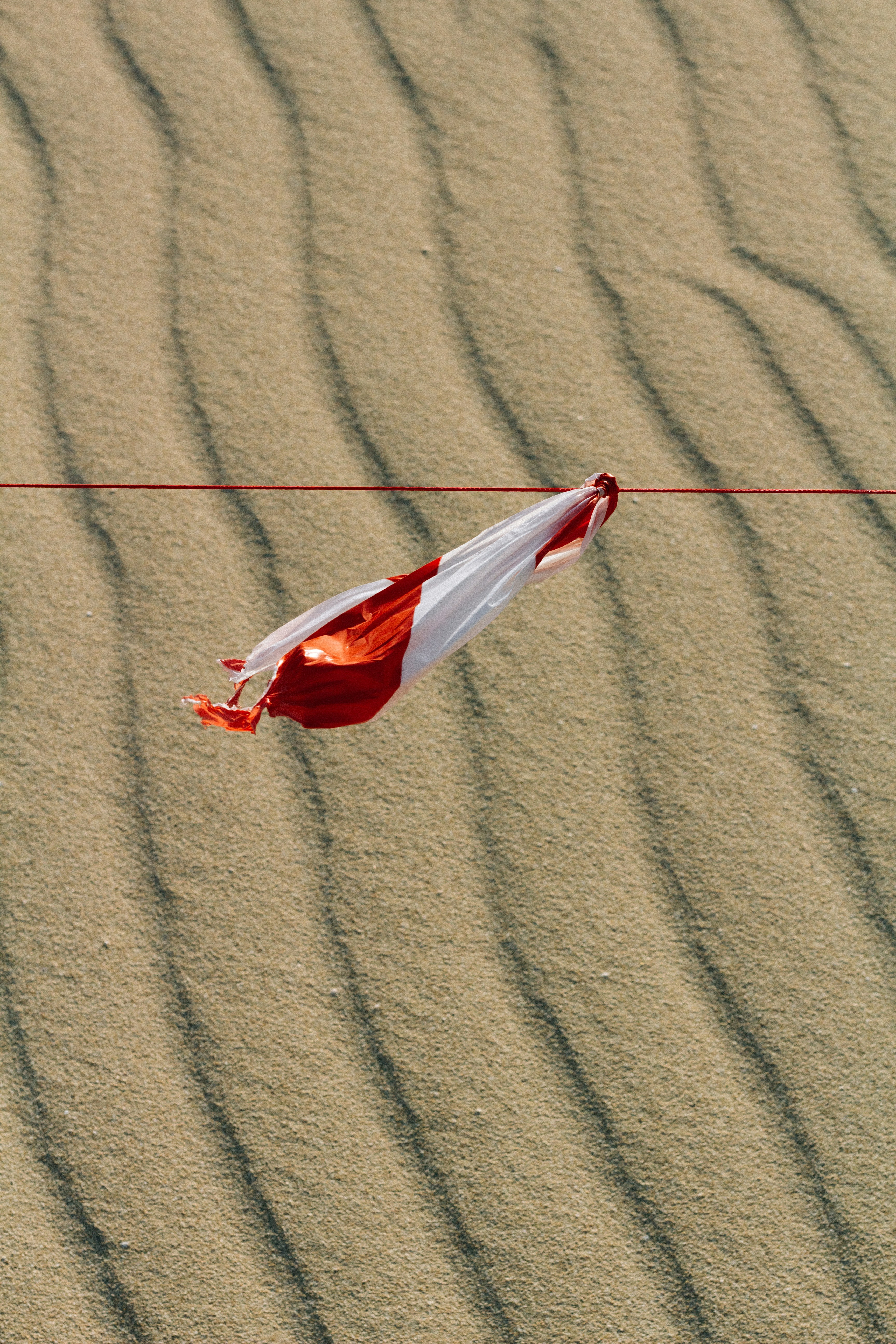 Knot in the Wind: Red-and-White Flag Across Desert Dunes