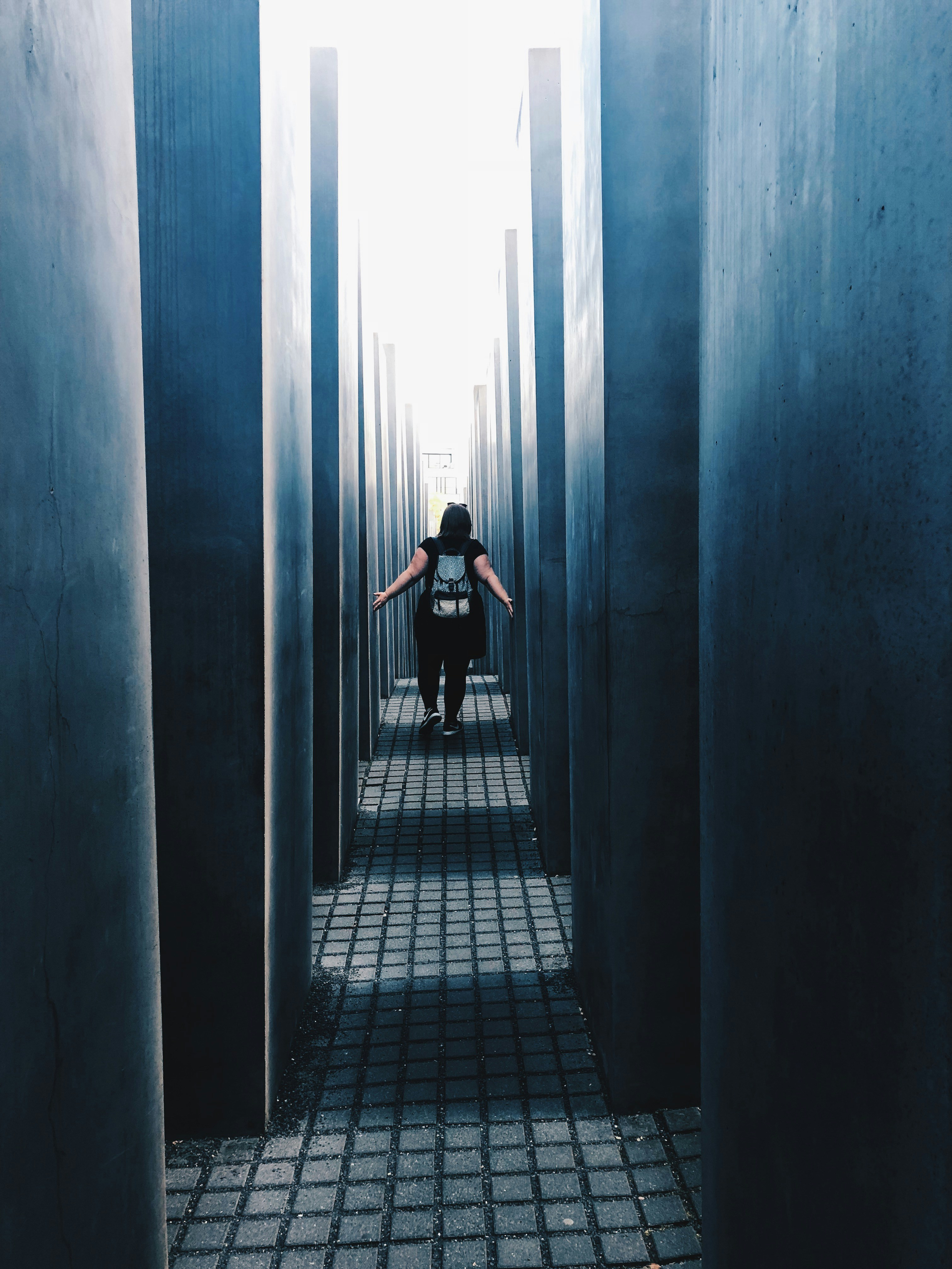 Between Monoliths: A Lone Figure Traverses the Corridor of Steel
