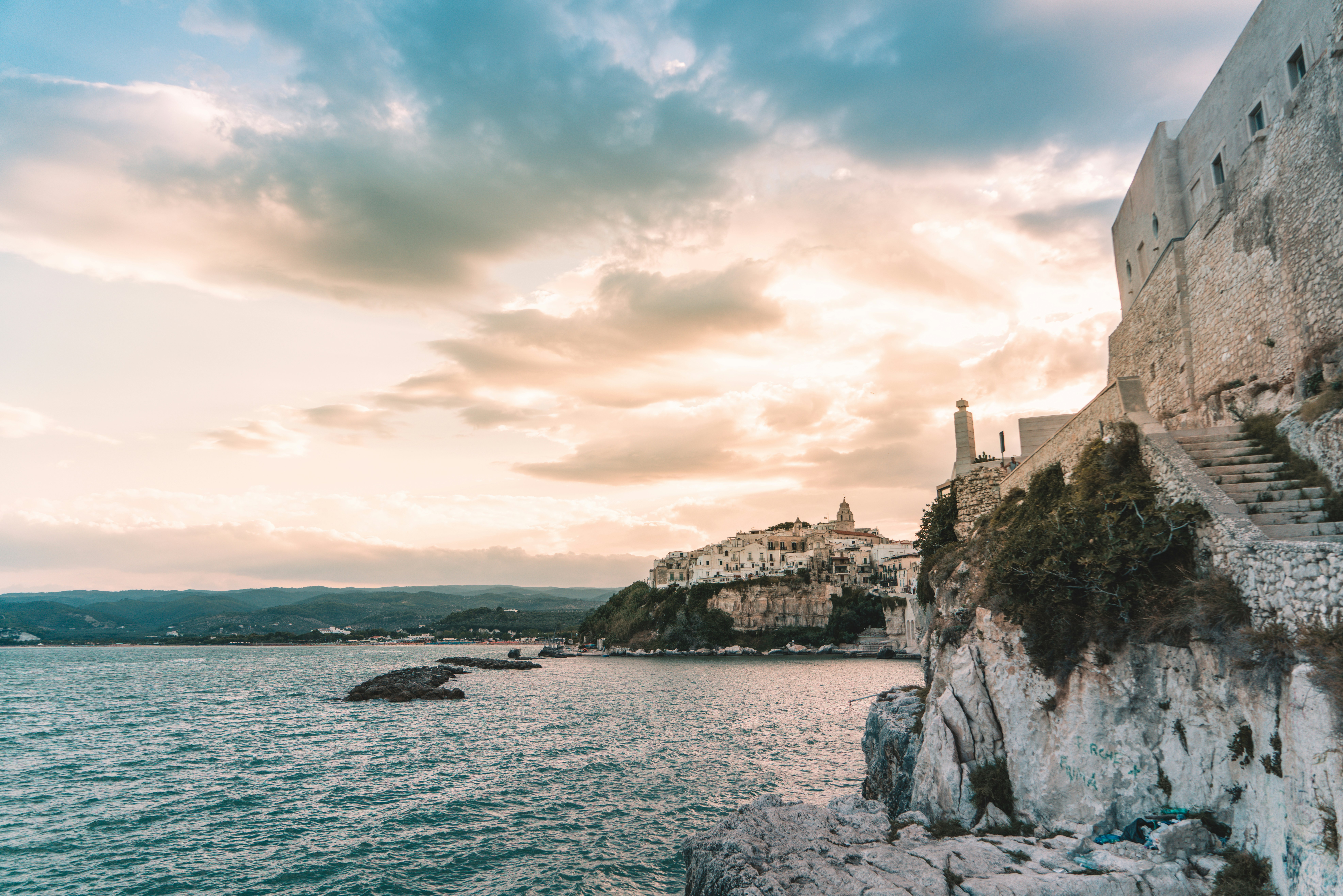 Coastal cliffs of Vieste in Puglia, Italy, under a golden sunset sky.