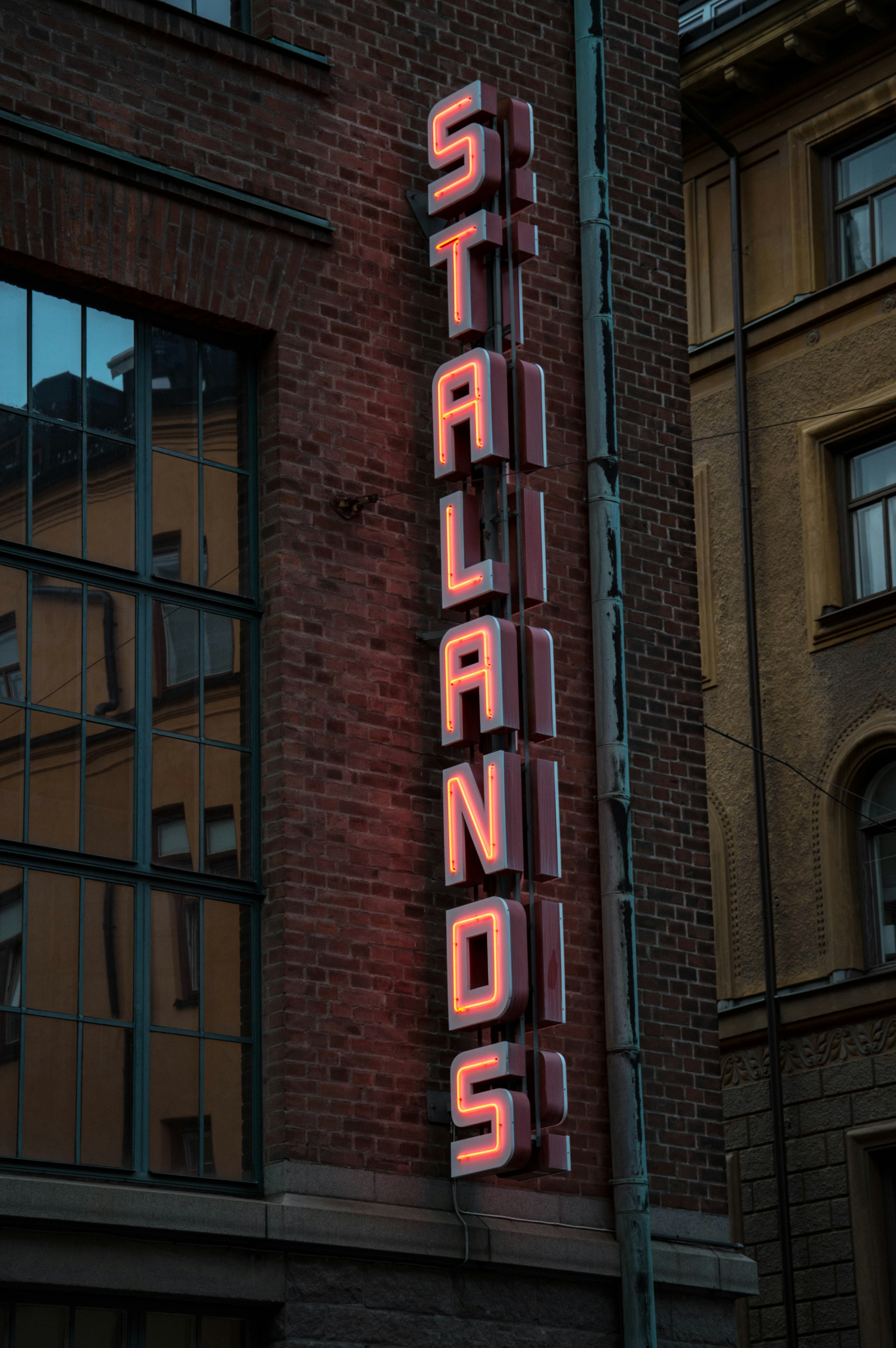 Vertical Neon on Brick: STALANDS Illuminates a Quiet Street