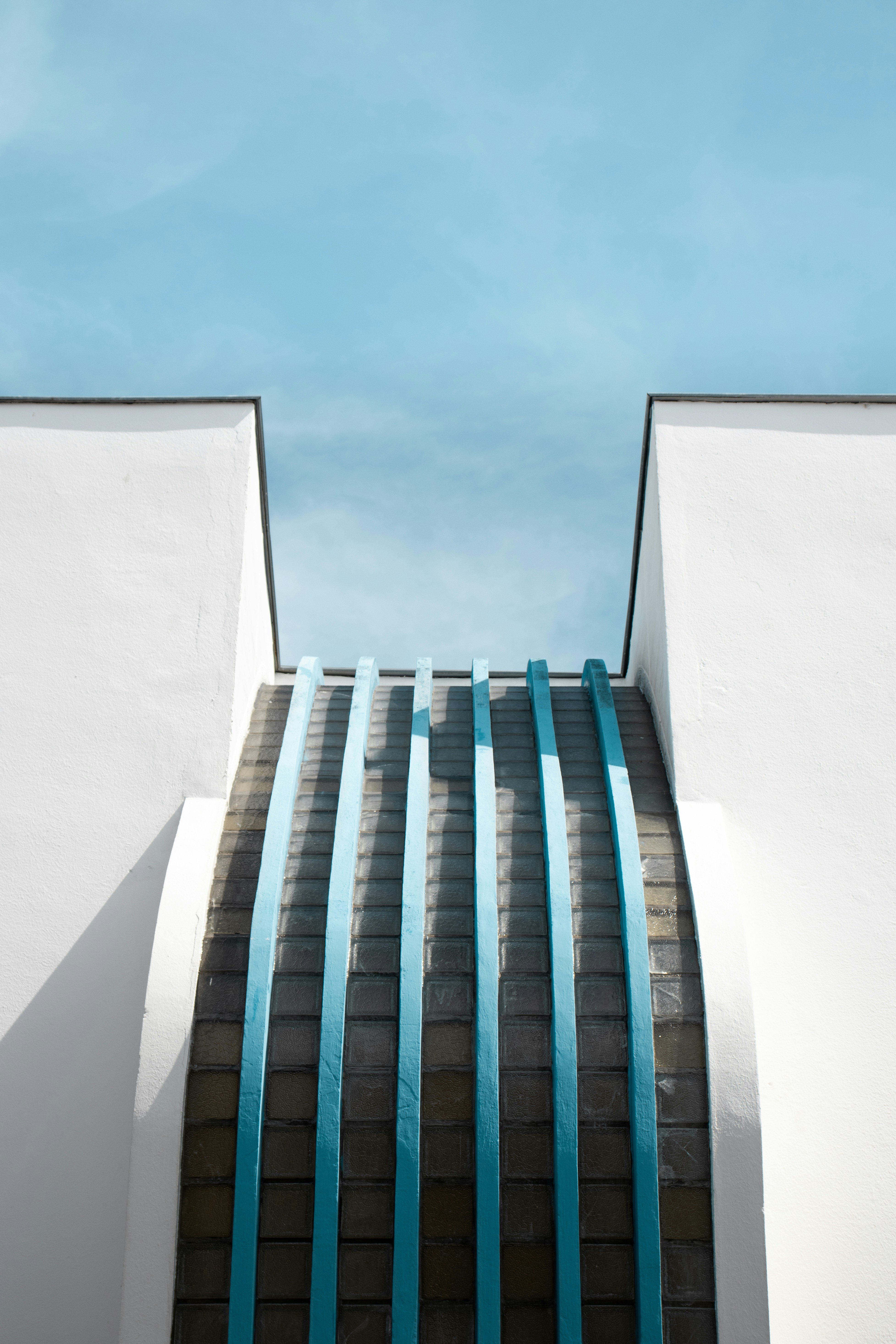 A striking architectural feature with blue lines contrasting against white walls and a clear sky above.