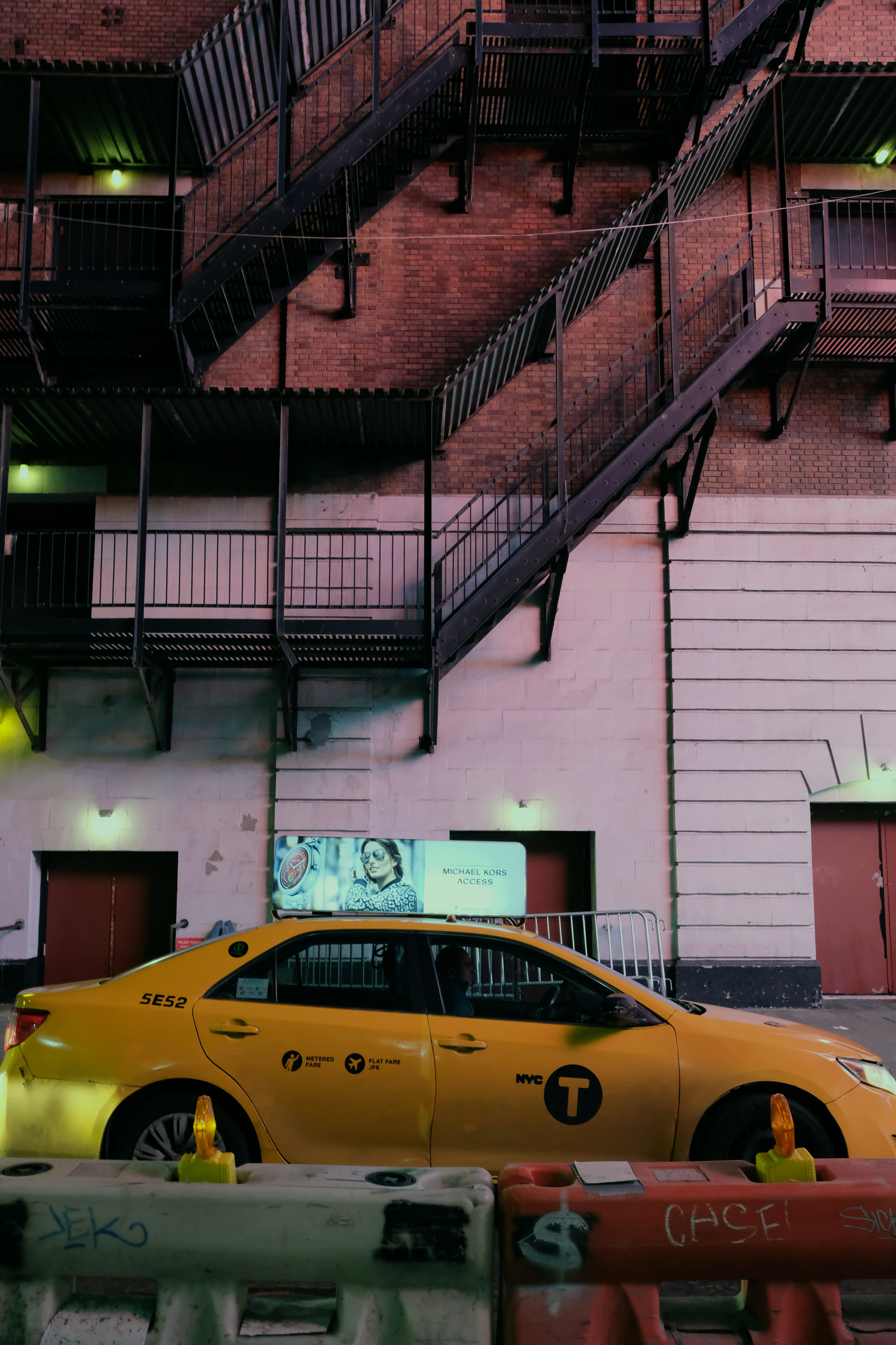 Yellow NYC Taxi Framed by an Urban Fire Escape at Dusk