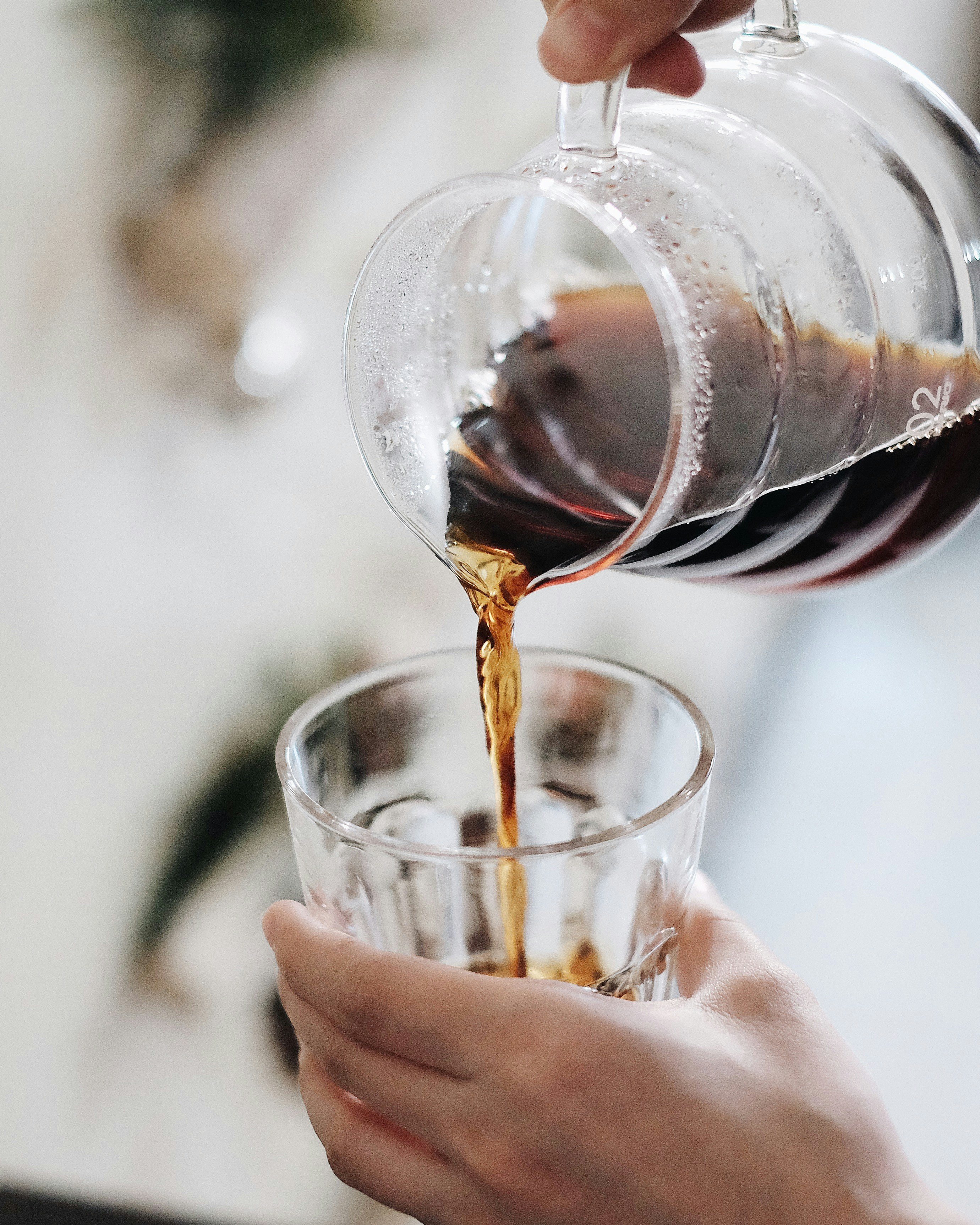 Coffee being poured from a glass carafe into a clear glass, capturing the essence of a morning ritual.