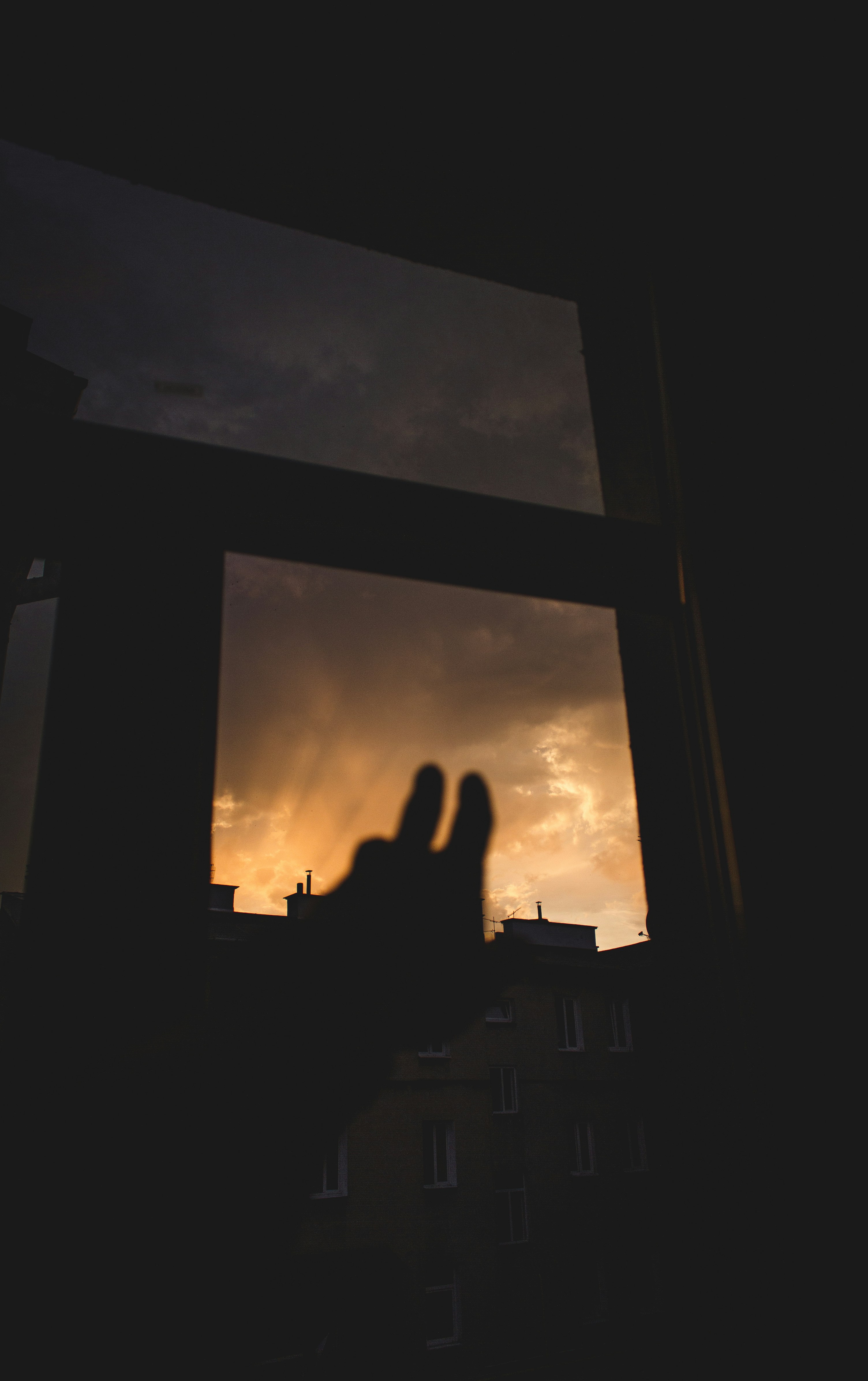 Framed Silence: A Hand Steadfast Against Sunset Through a Window
