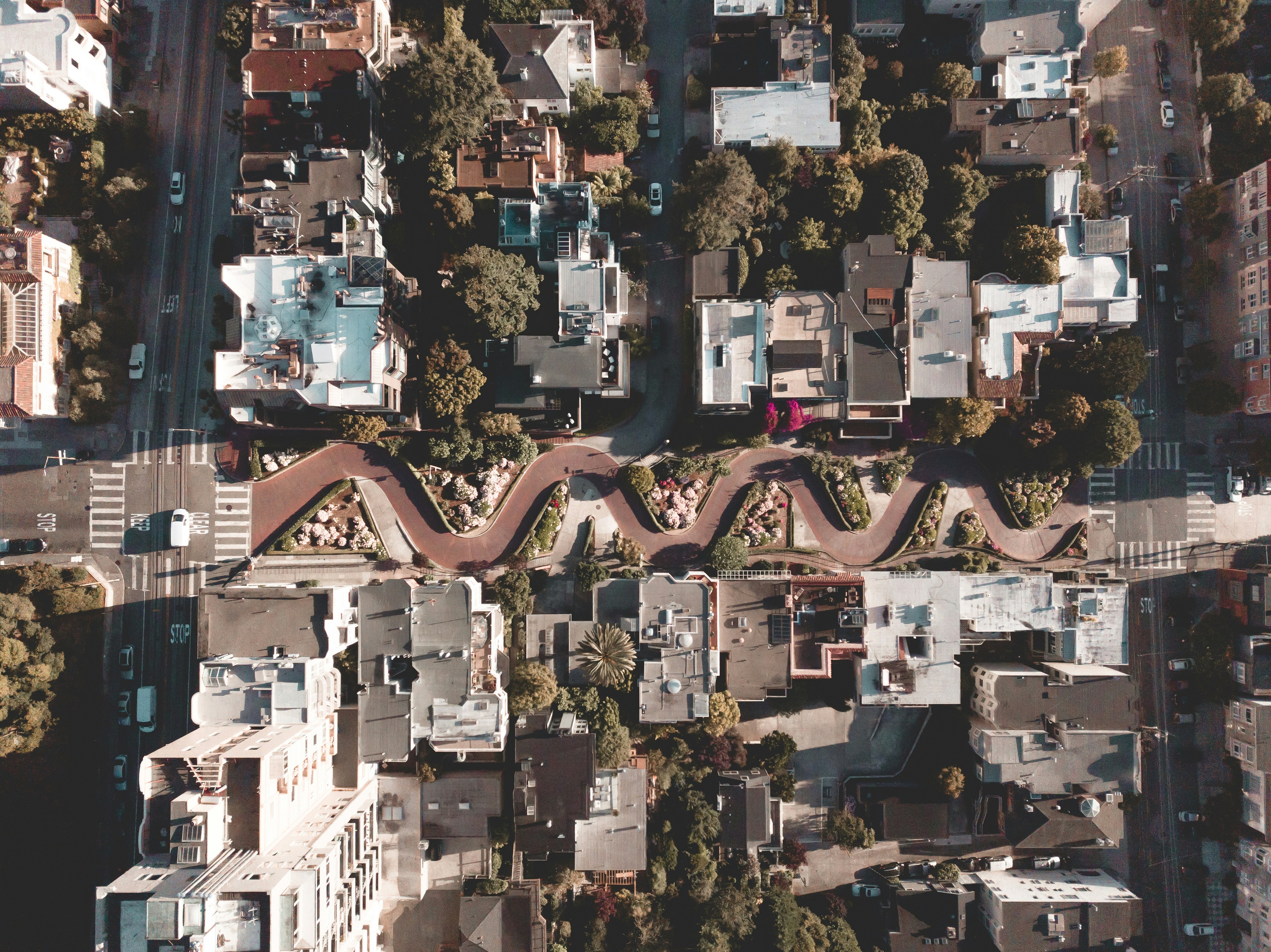 Aerial view of the zigzagging Lombard Street in San Francisco surrounded by urban architecture and greenery.