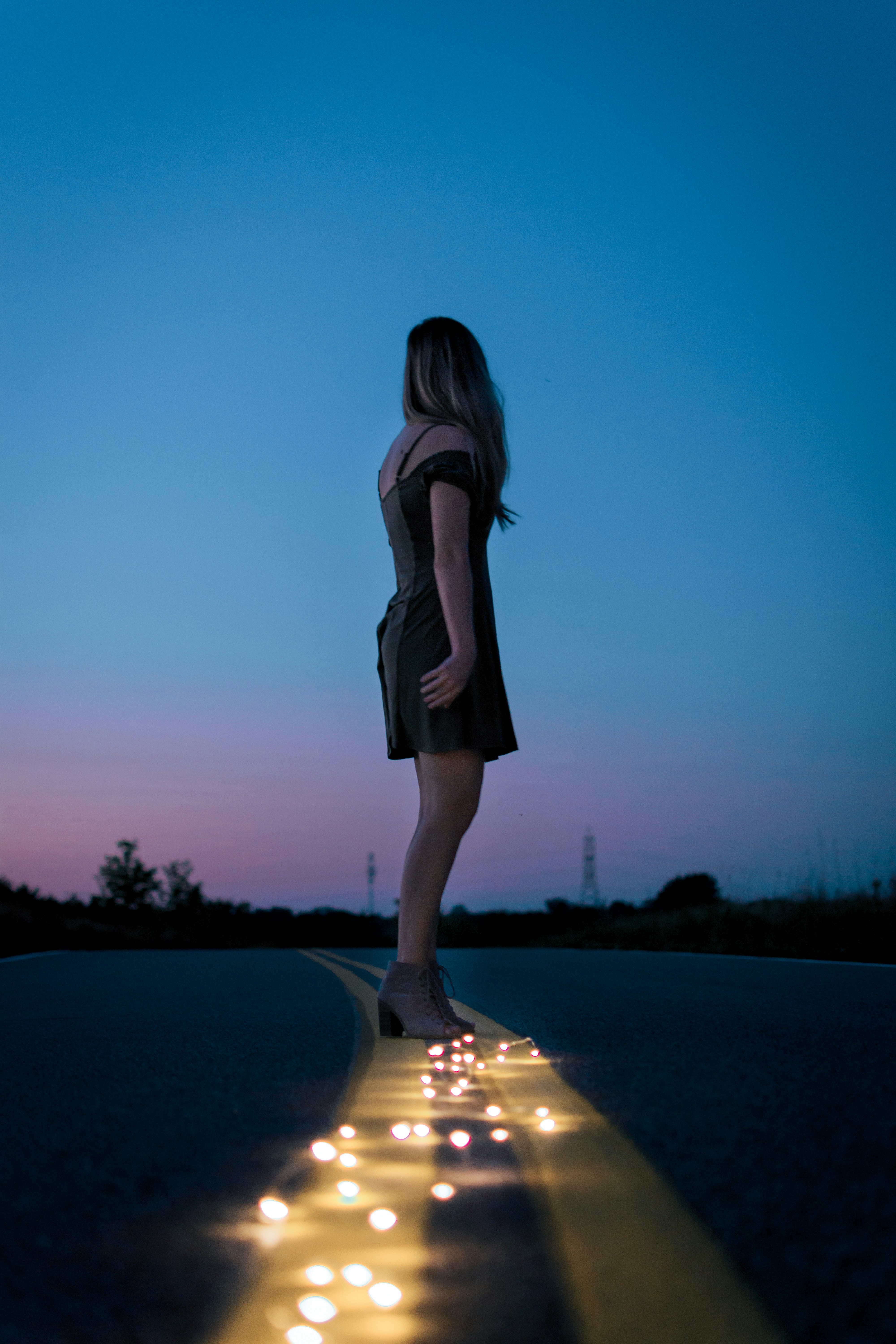 Dusk on the Line: A lone figure balances along a glow-lit highway stripe