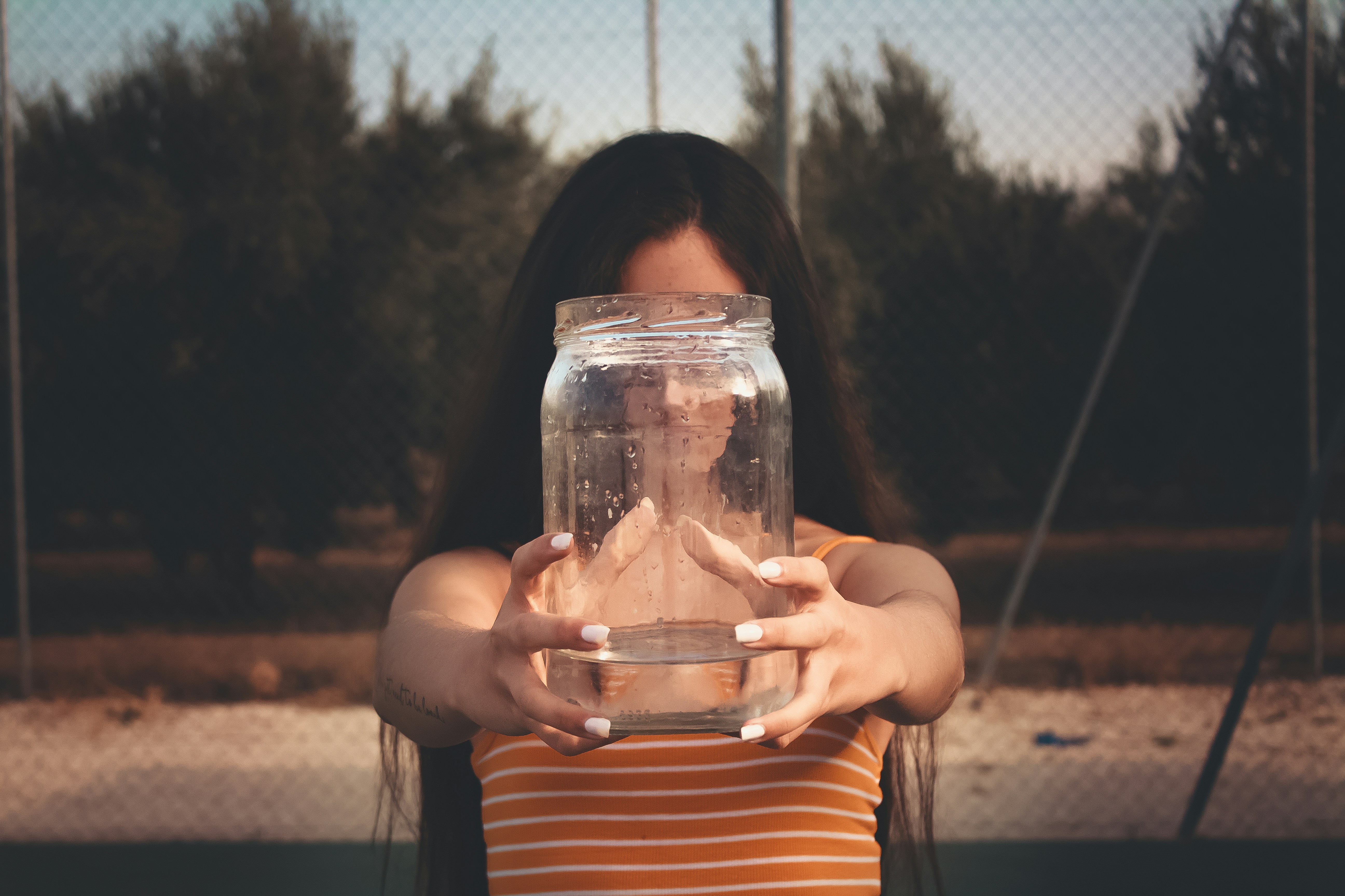 Holding Still: A Clear Jar Clasped by Extended Arms