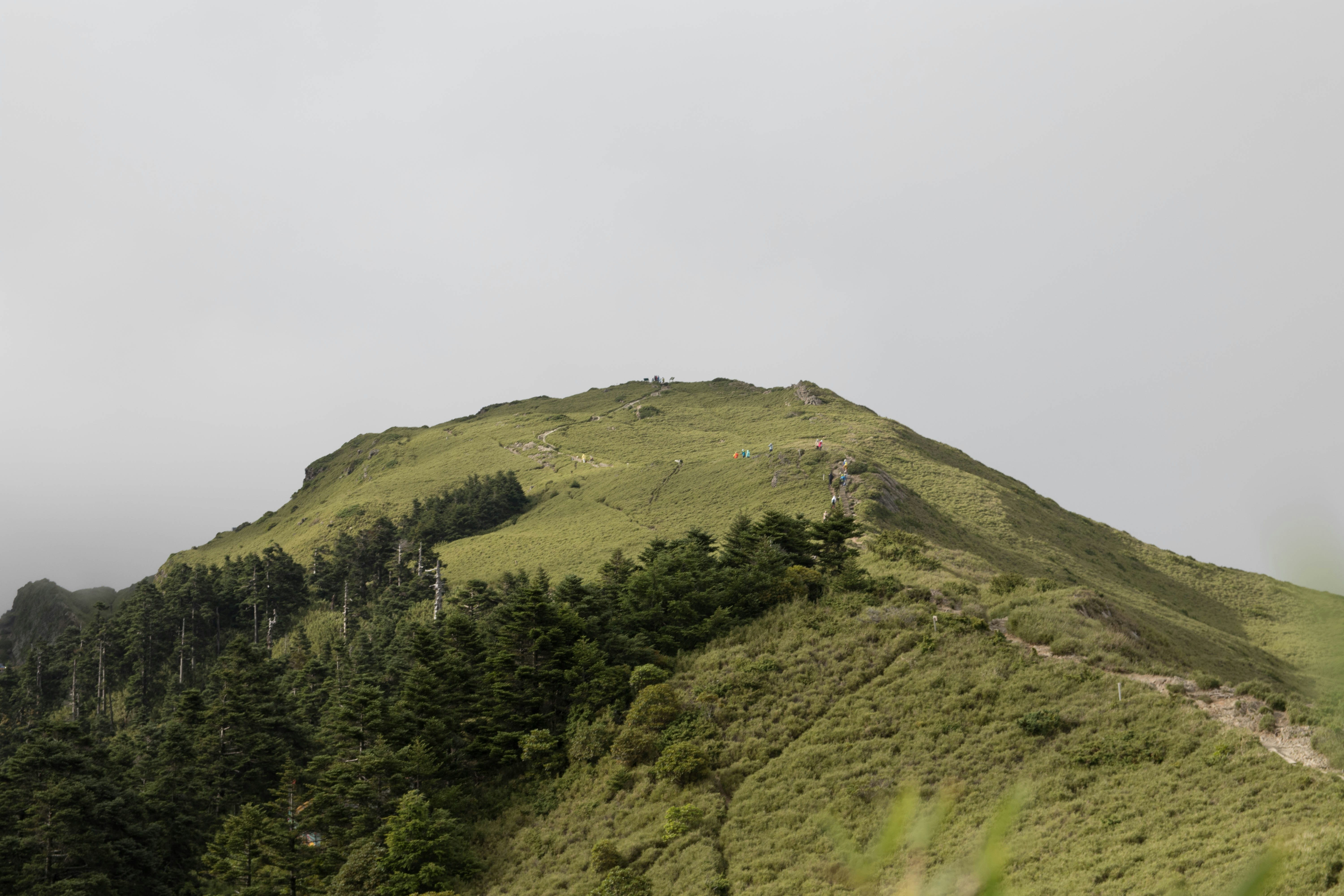 Lush green hillside leading to a rugged peak under a cloudy sky. The landscape invites exploration and adventure.