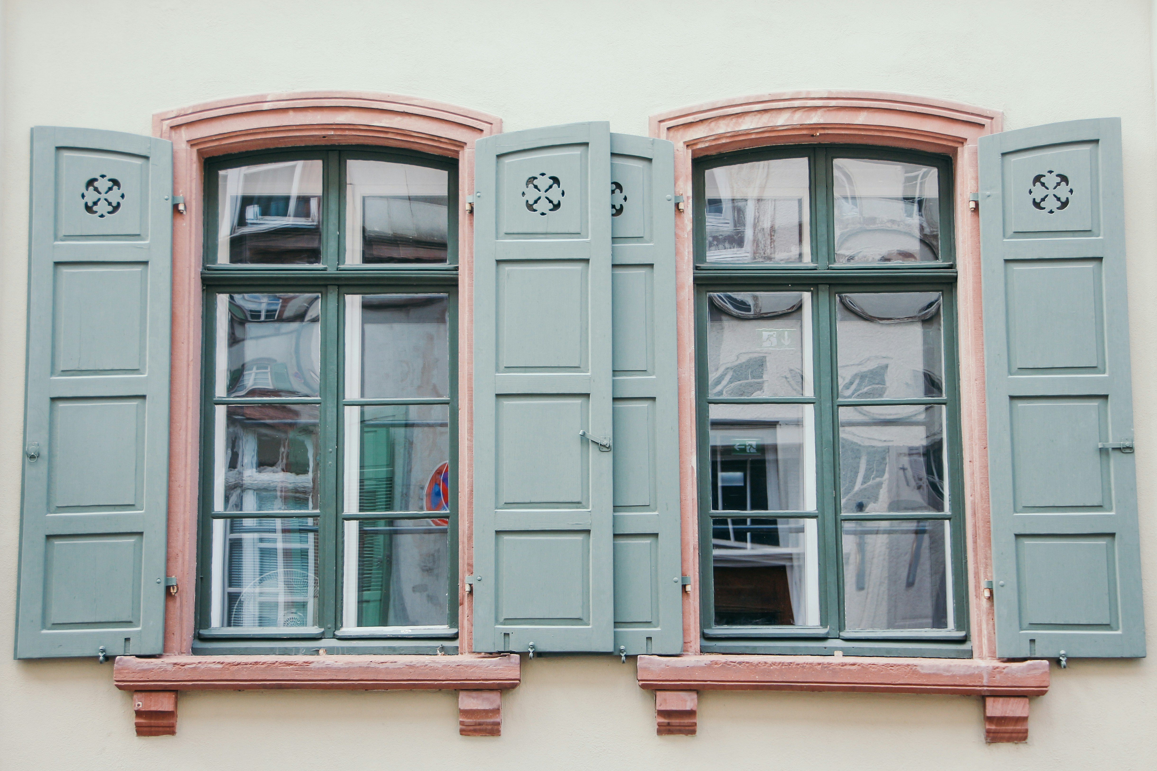 Two pastel-colored windows with shutters on a light facade, reflecting subtle architectural details.