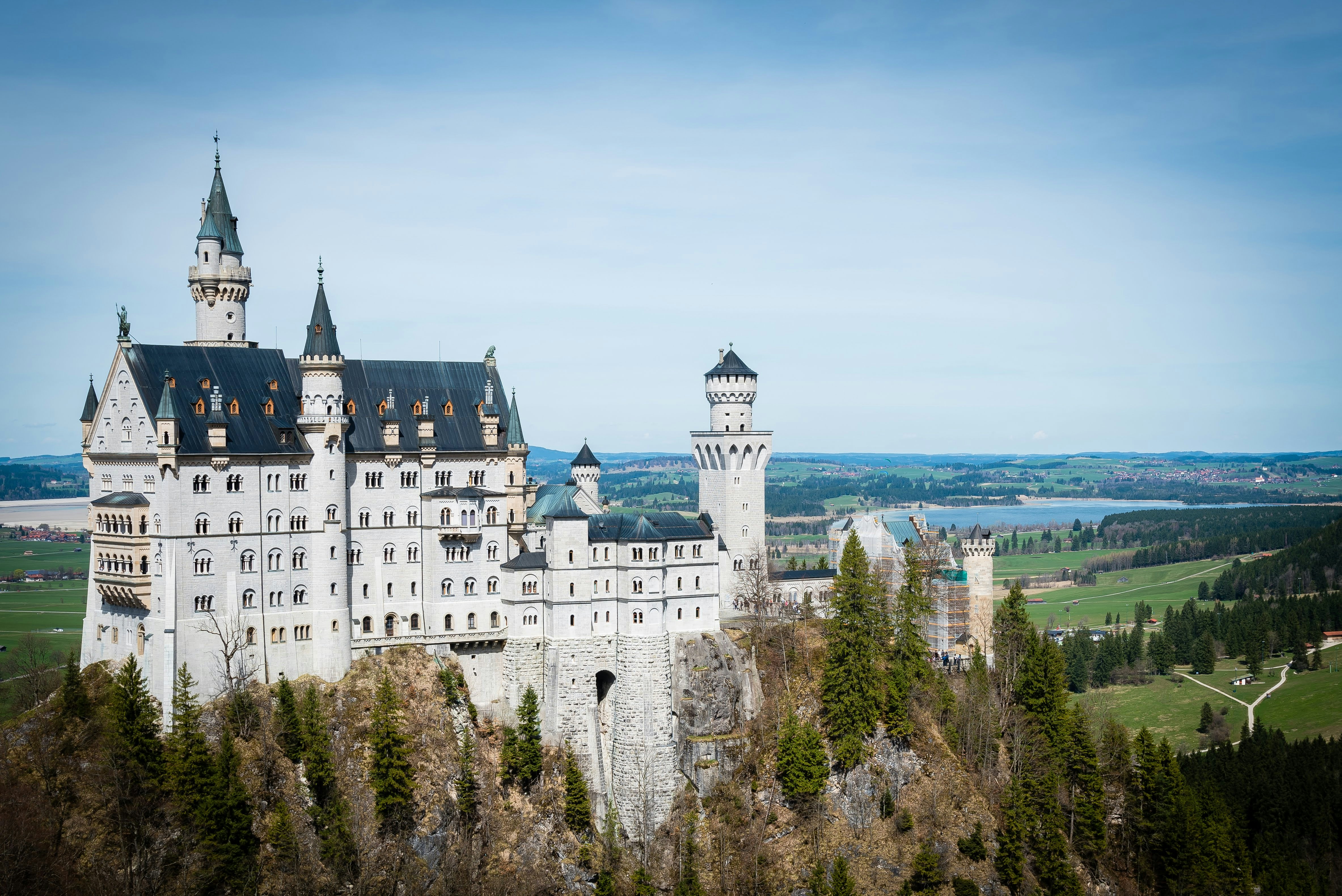 White and blue concrete castle surrounded by green trees under blue sky ...