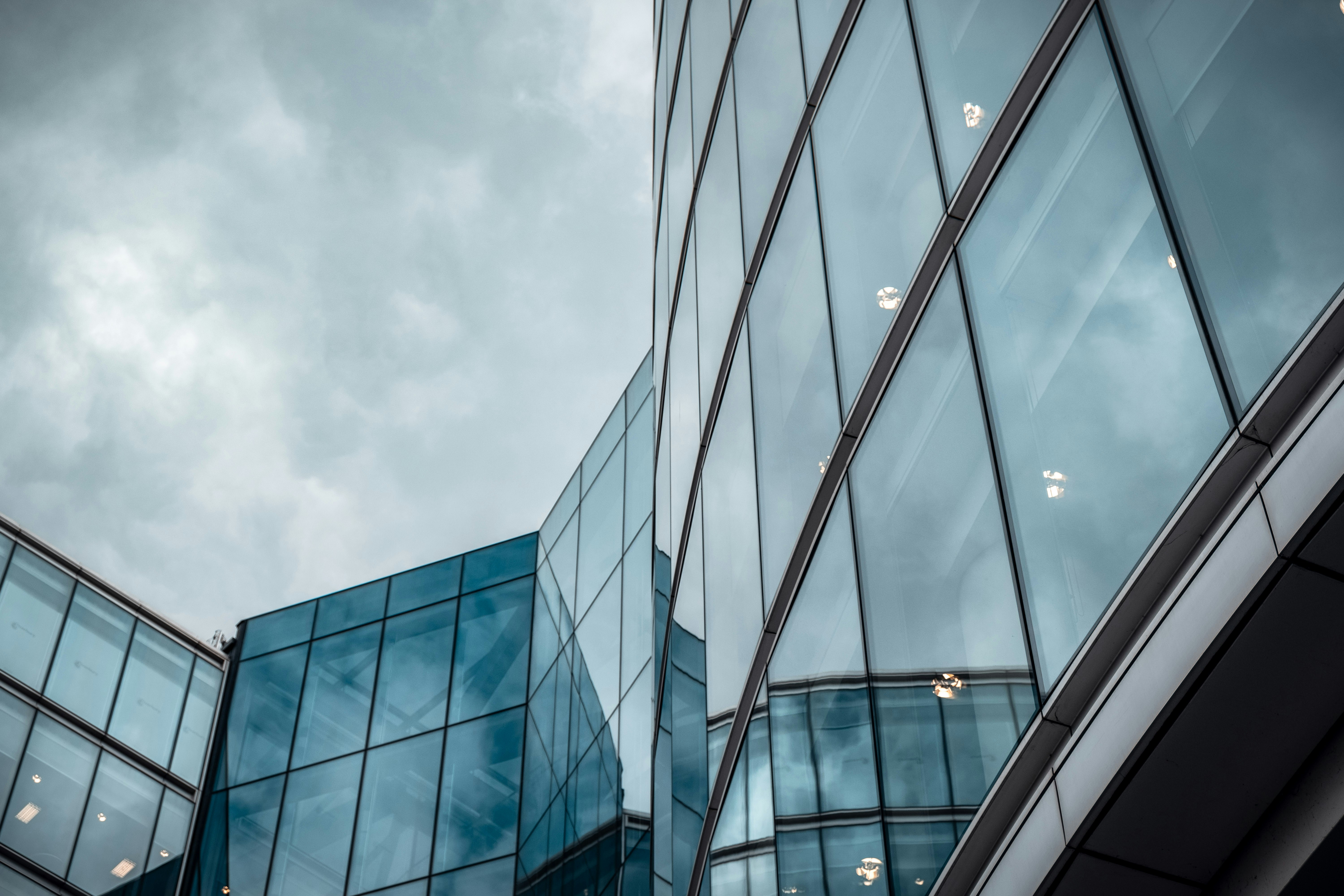 Glass buildings reflecting the overcast sky in an urban landscape.