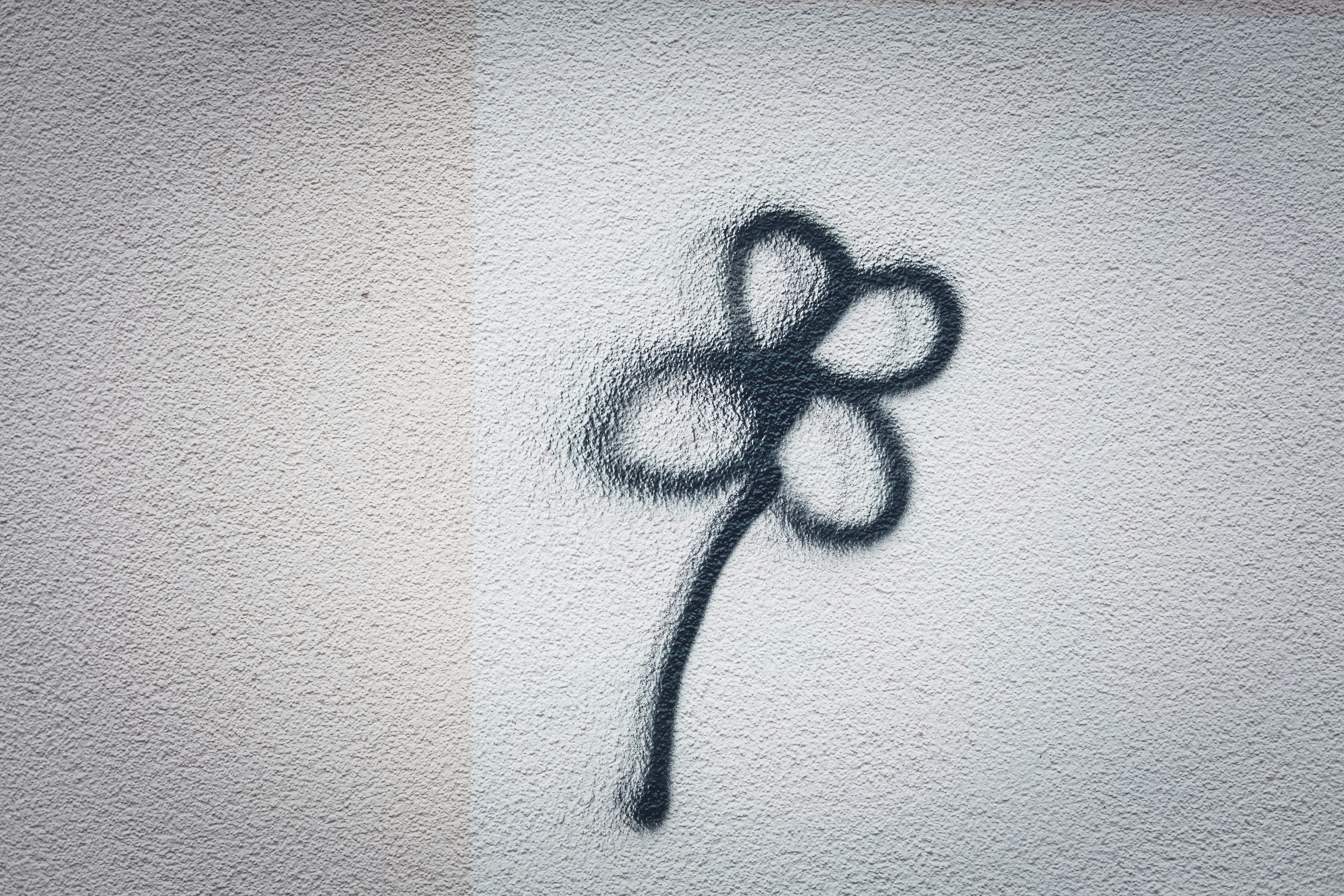 Spray-Stamped Clover: a Minimal Four-Leaf Graffiti on a Textured Wall