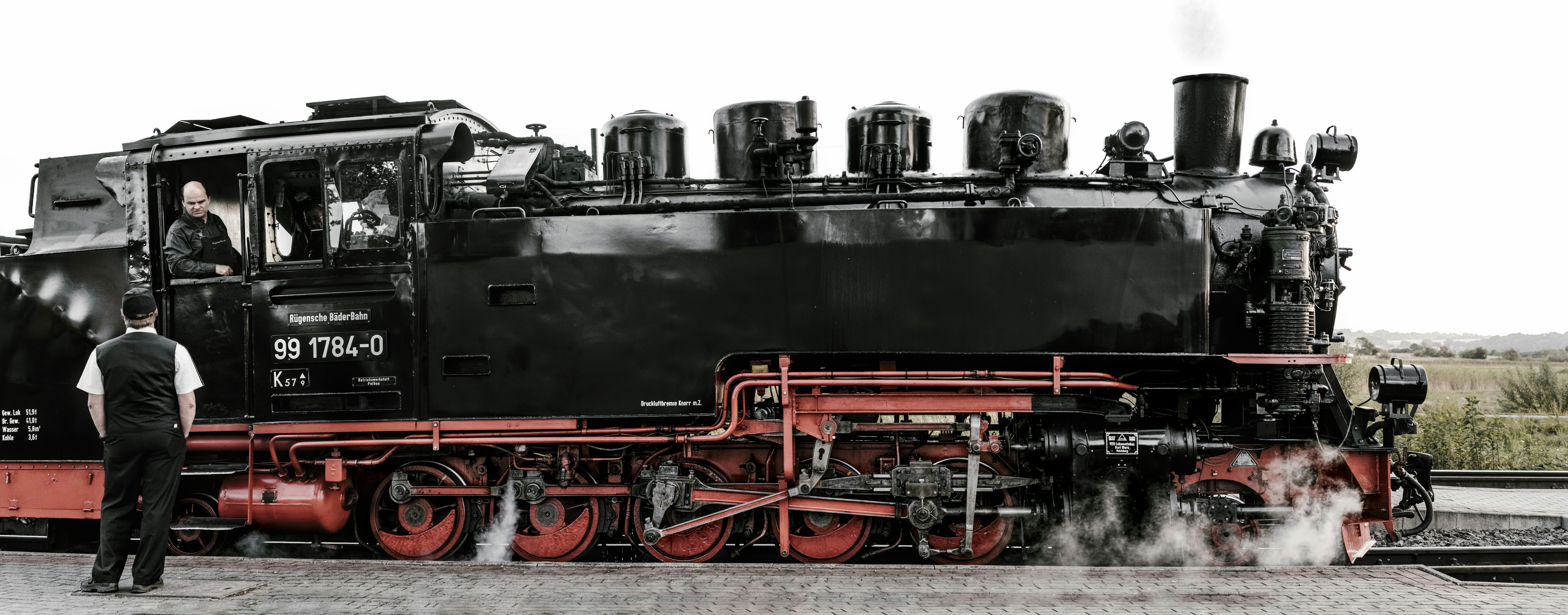 A vintage steam locomotive stands proudly at the station, showcasing its intricate mechanical details and historical significance.