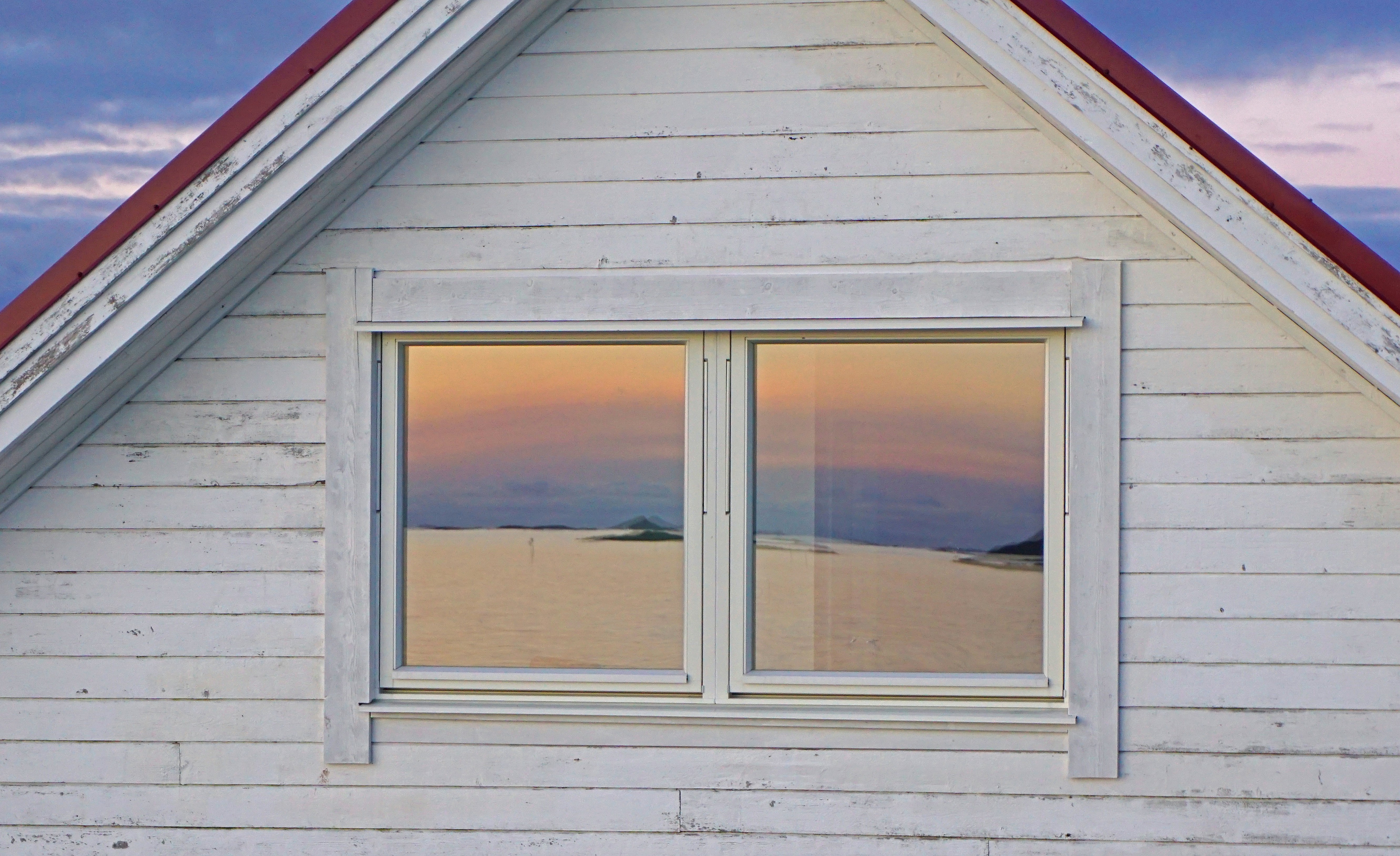 Twin Windows Reflect a Quiet Sunset on a Weathered White Wall