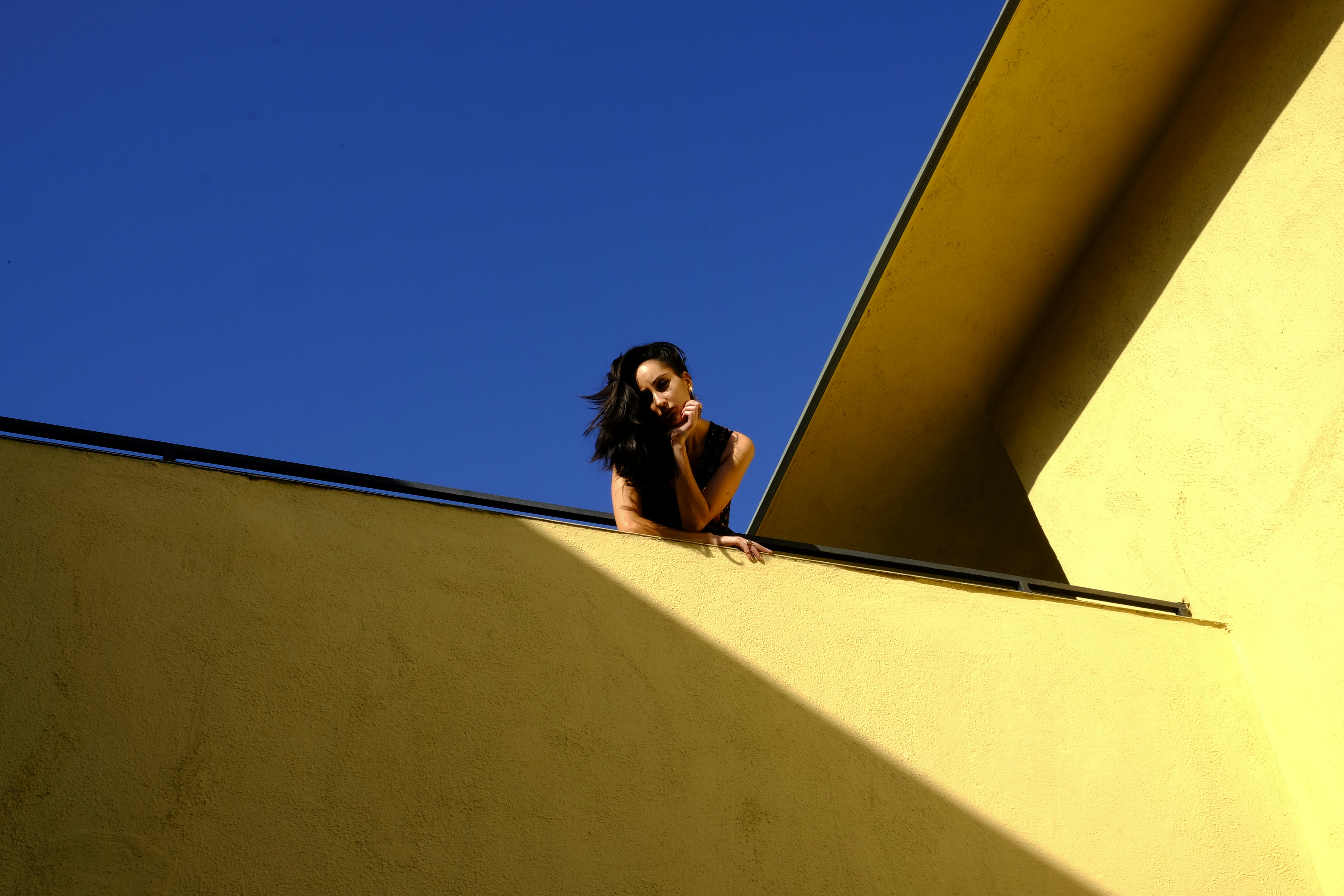 Over the Yellow Edge: Portrait on a Daring Balcony beneath Azure Sky