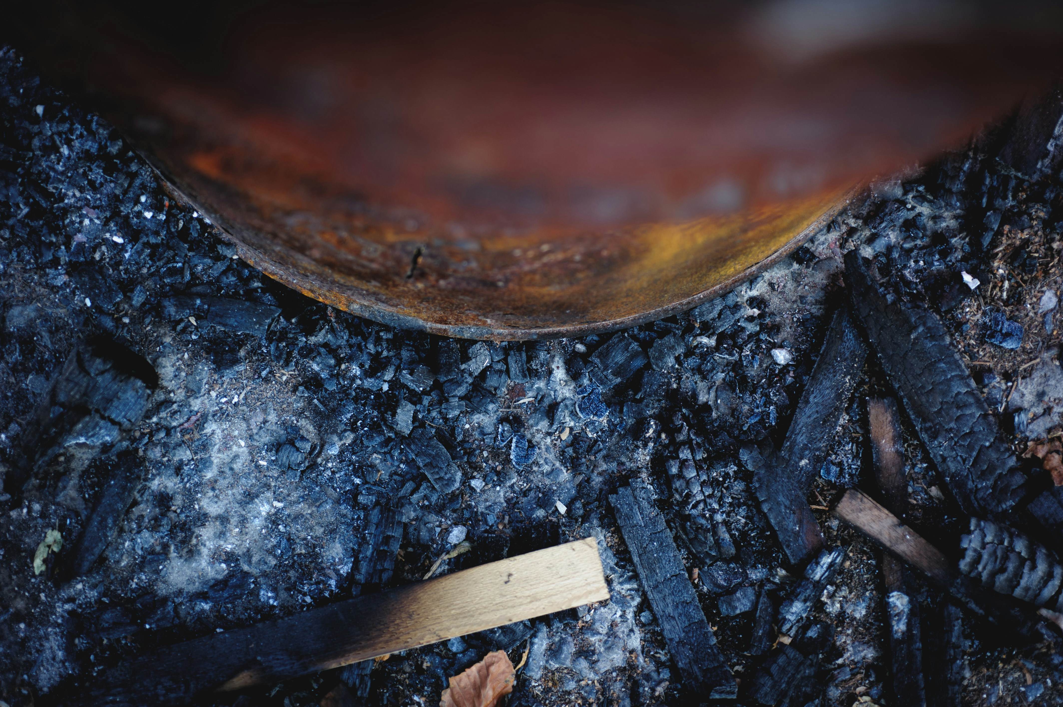 A metal object sitting on top of a pile of burned wood photo – Free ...