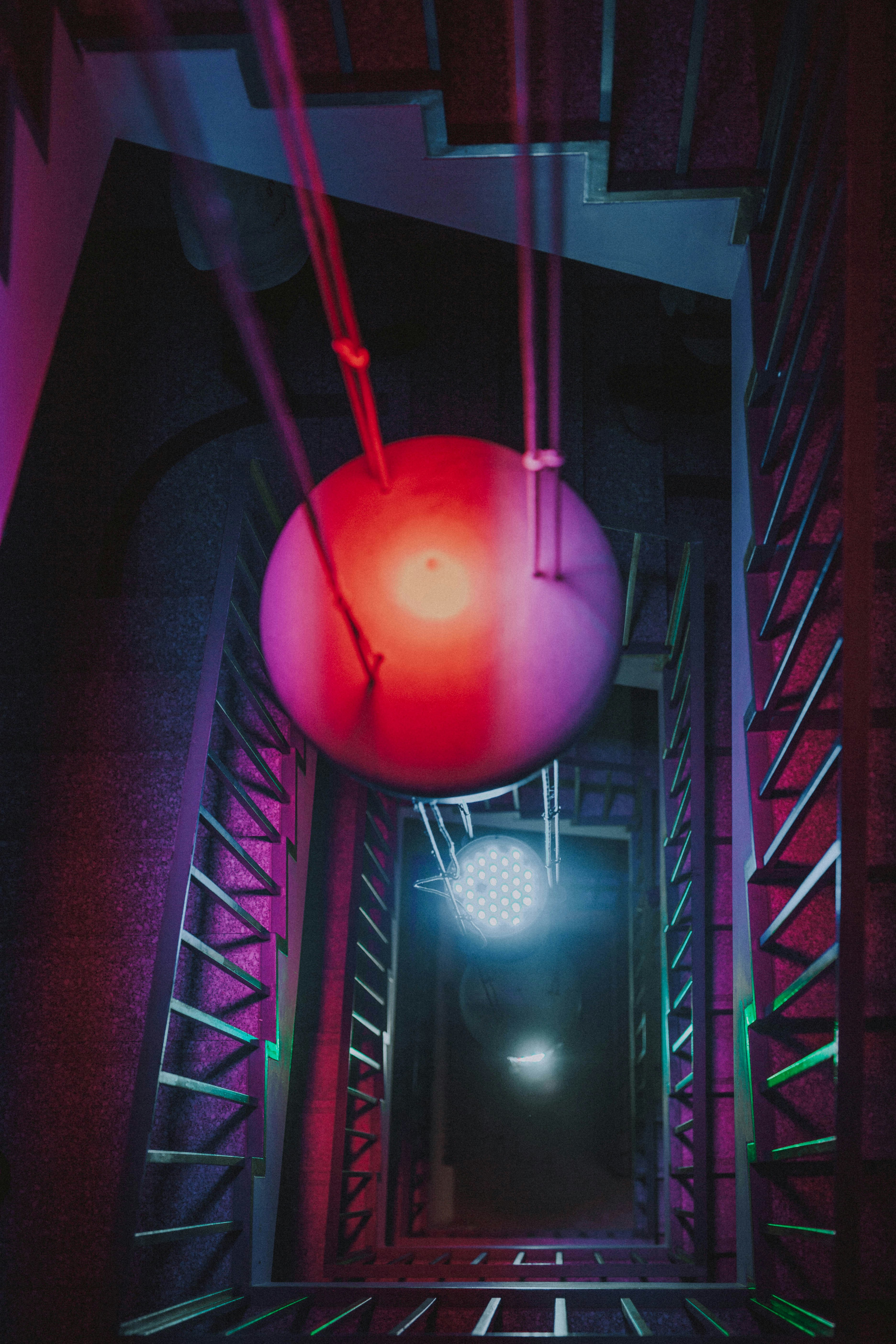 Suspended Orb in Neon Stairwell Cascade