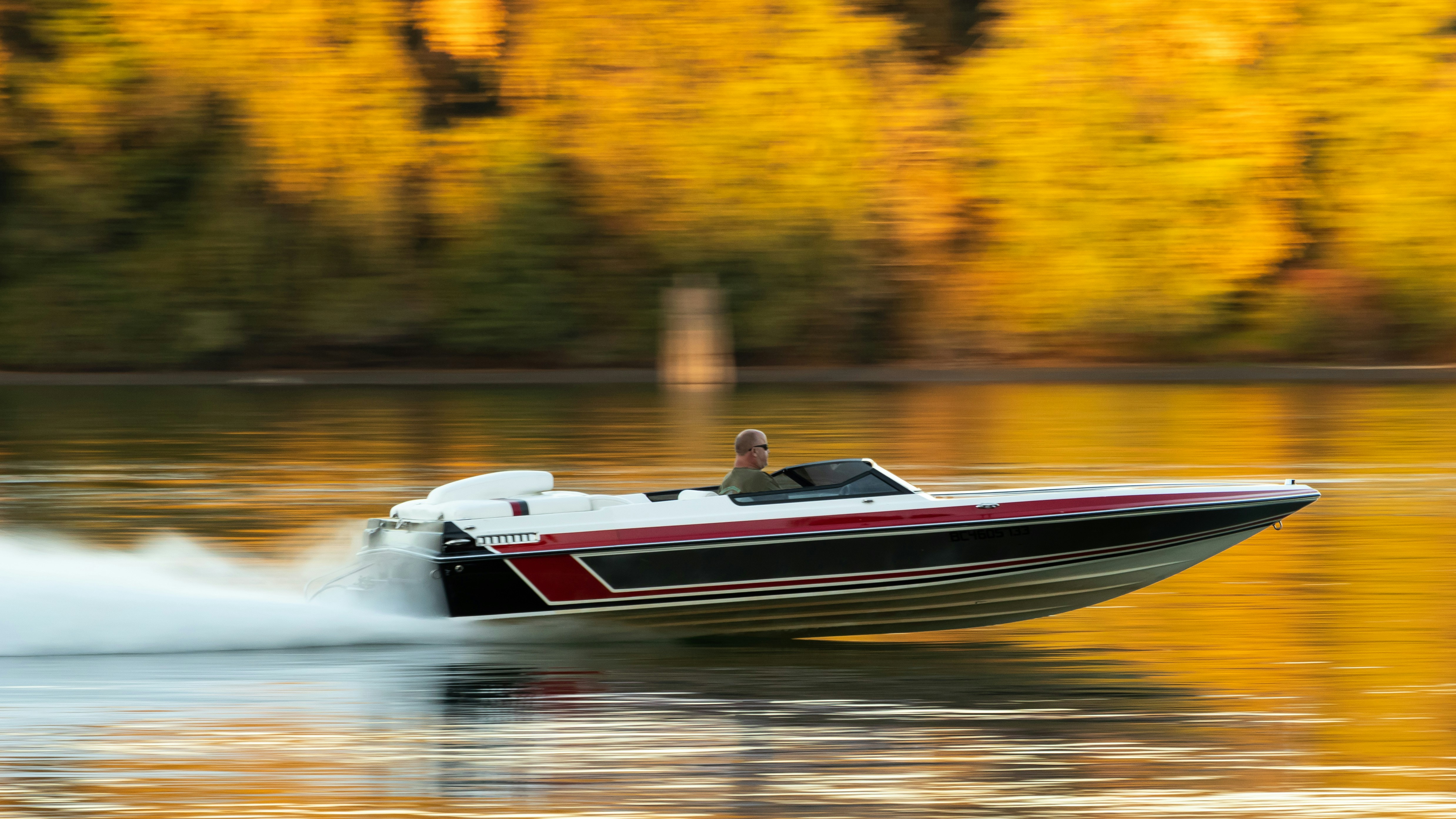Jetboat in Autumn | person driving black and gray speed boat during daytime
