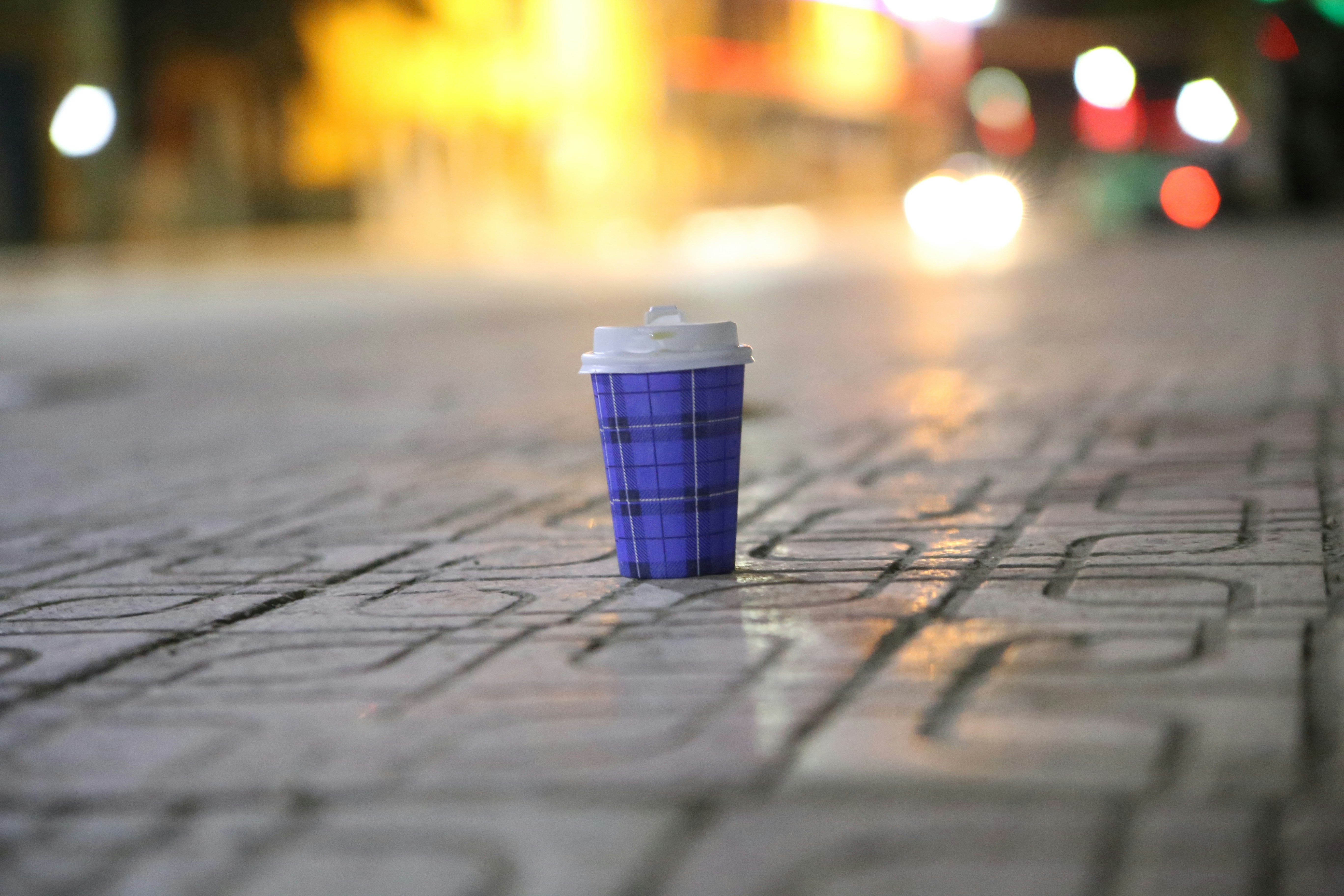 Blue Plaid Takeout Cup on Dusk-Glowing Cobblestones