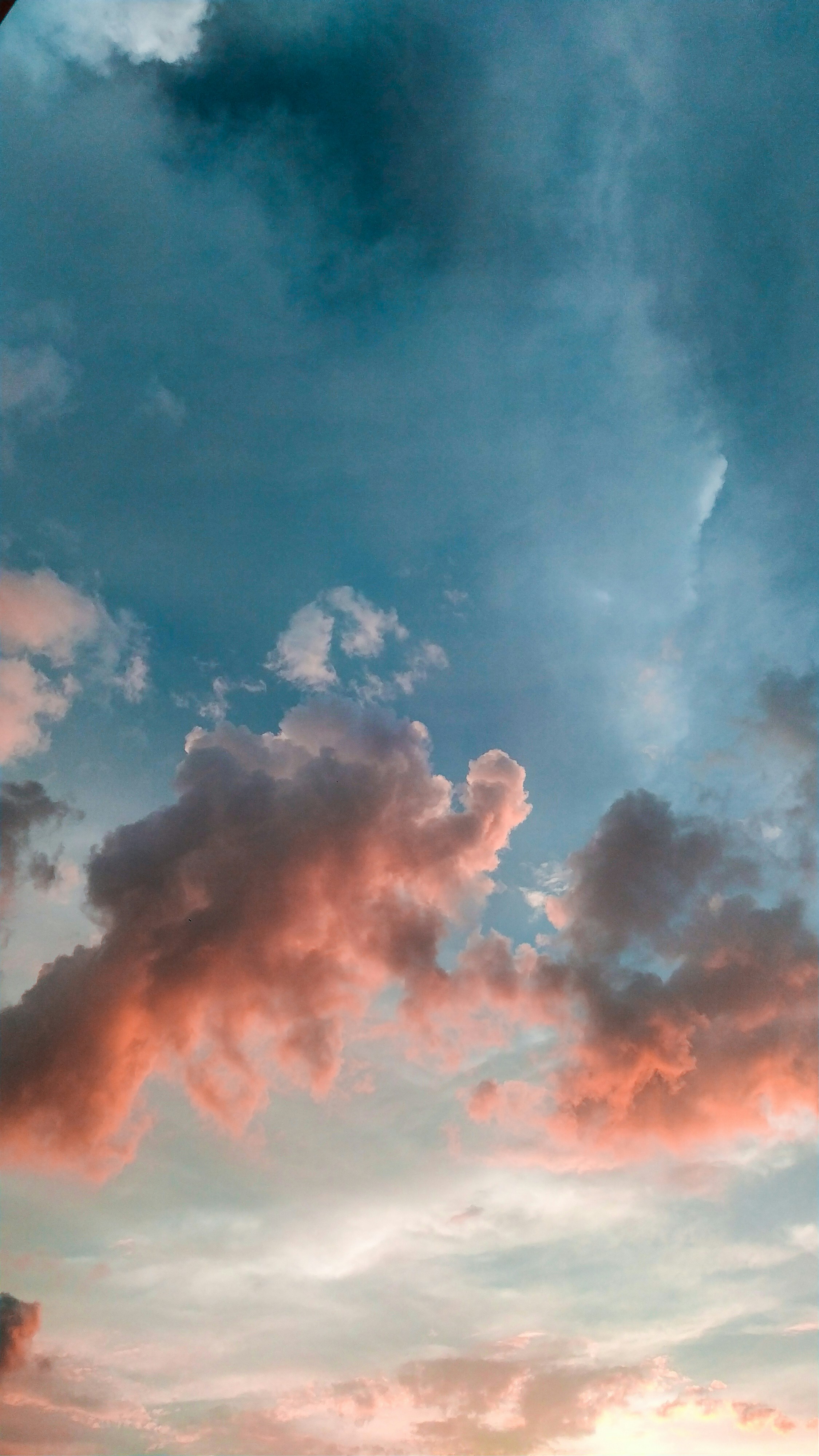 Vibrant clouds painted in shades of pink and orange drift across a serene blue sky, capturing the essence of twilight.